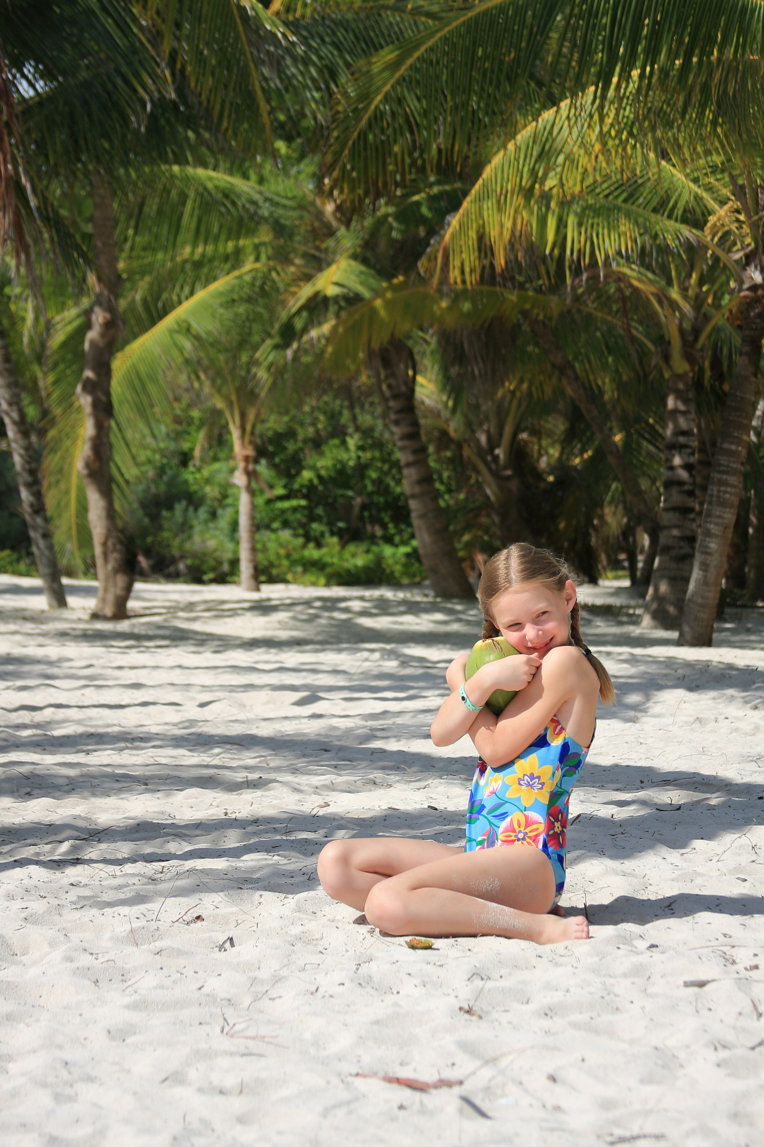 Sunlit Garden of Palm Shadows: A Girl in a Floral Swimsuit Embraces the Beach