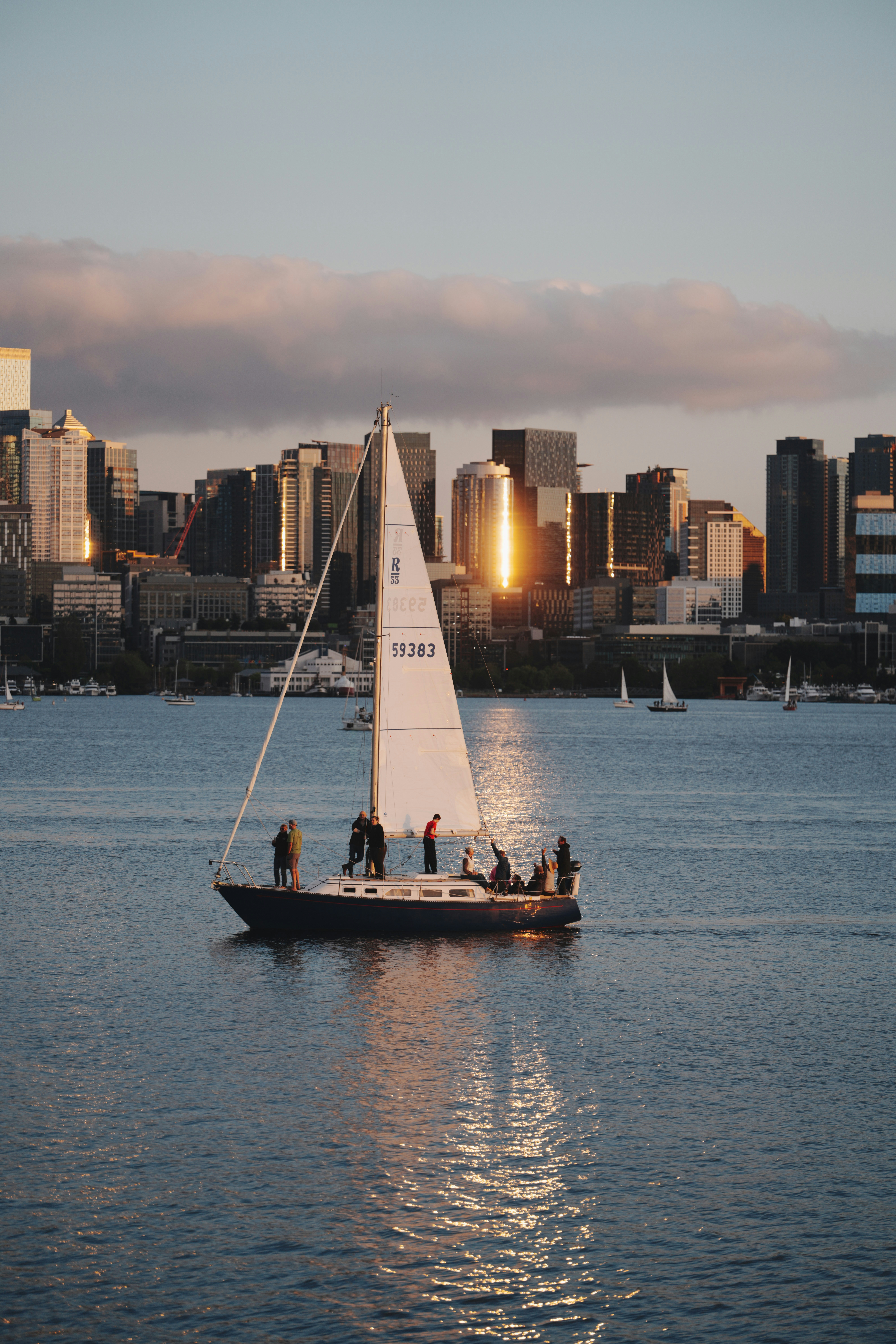 Sunlit Sail: City Skyline and a Sailboat on Quiet Waters