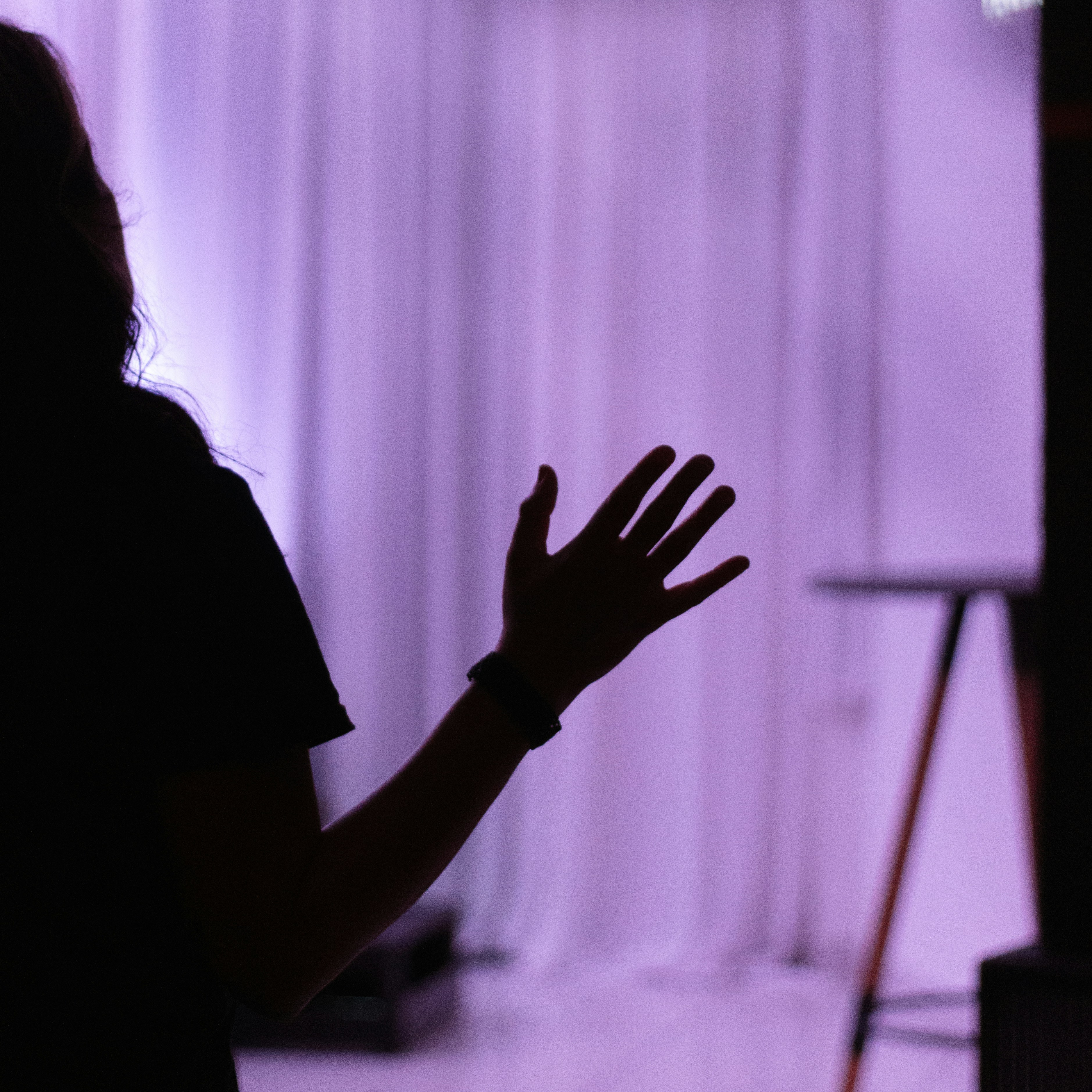 Gesture in a Purple Backdrop: A silhouette reaches toward the unseen