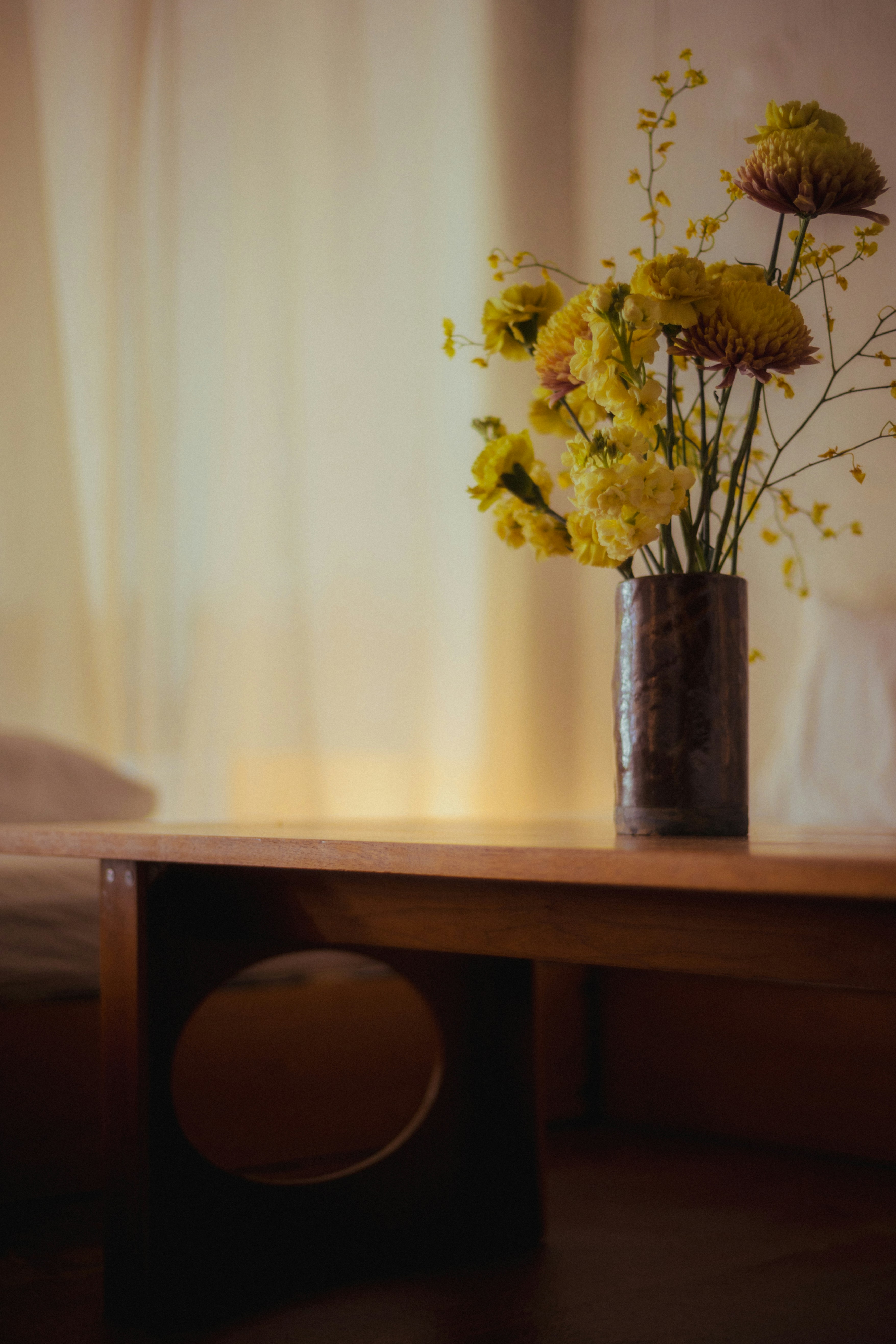 Yellow bouquet in a metallic vase on a wooden table