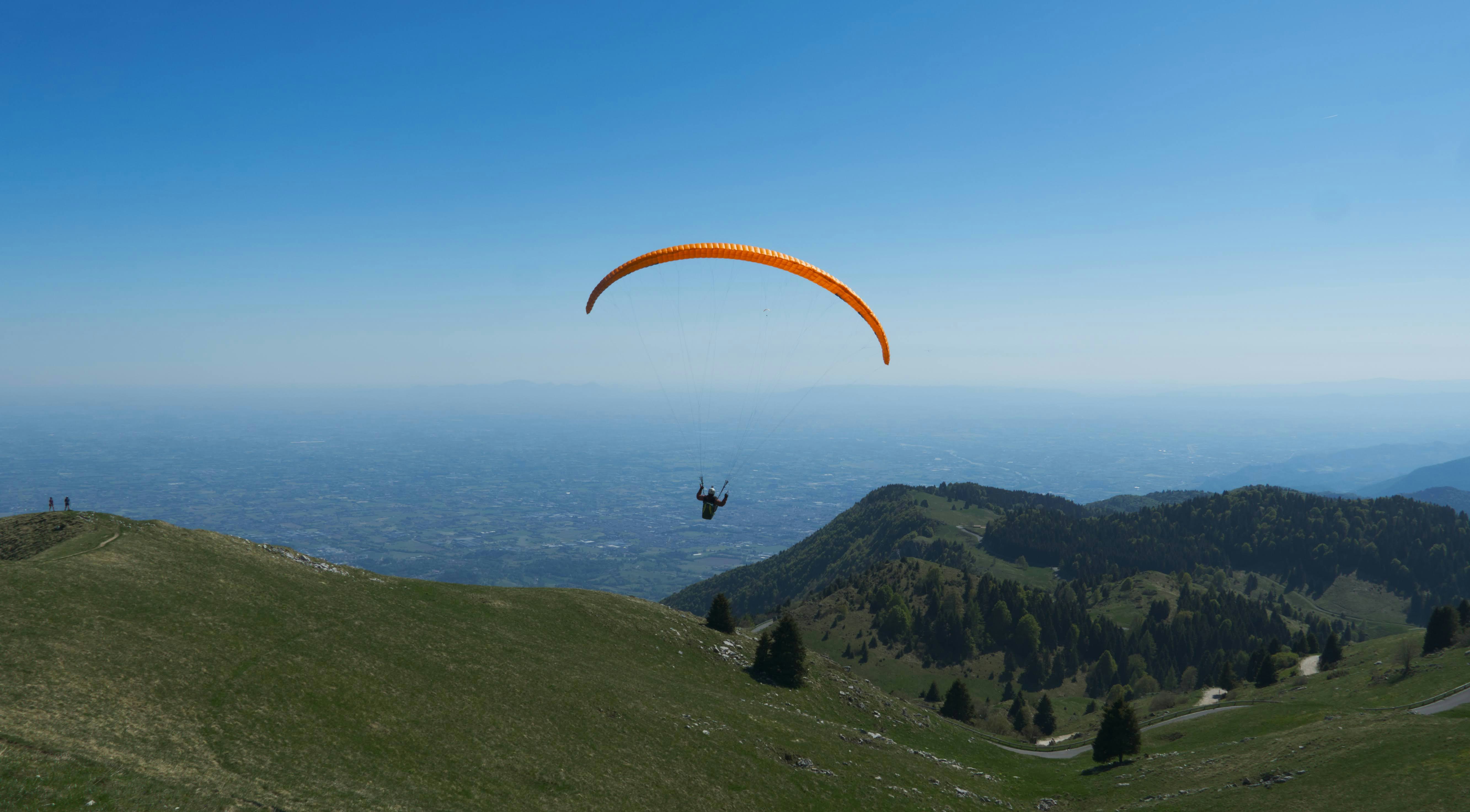 High Altitude Glide: A Paraglider Traces a Silhouette Above the Hills