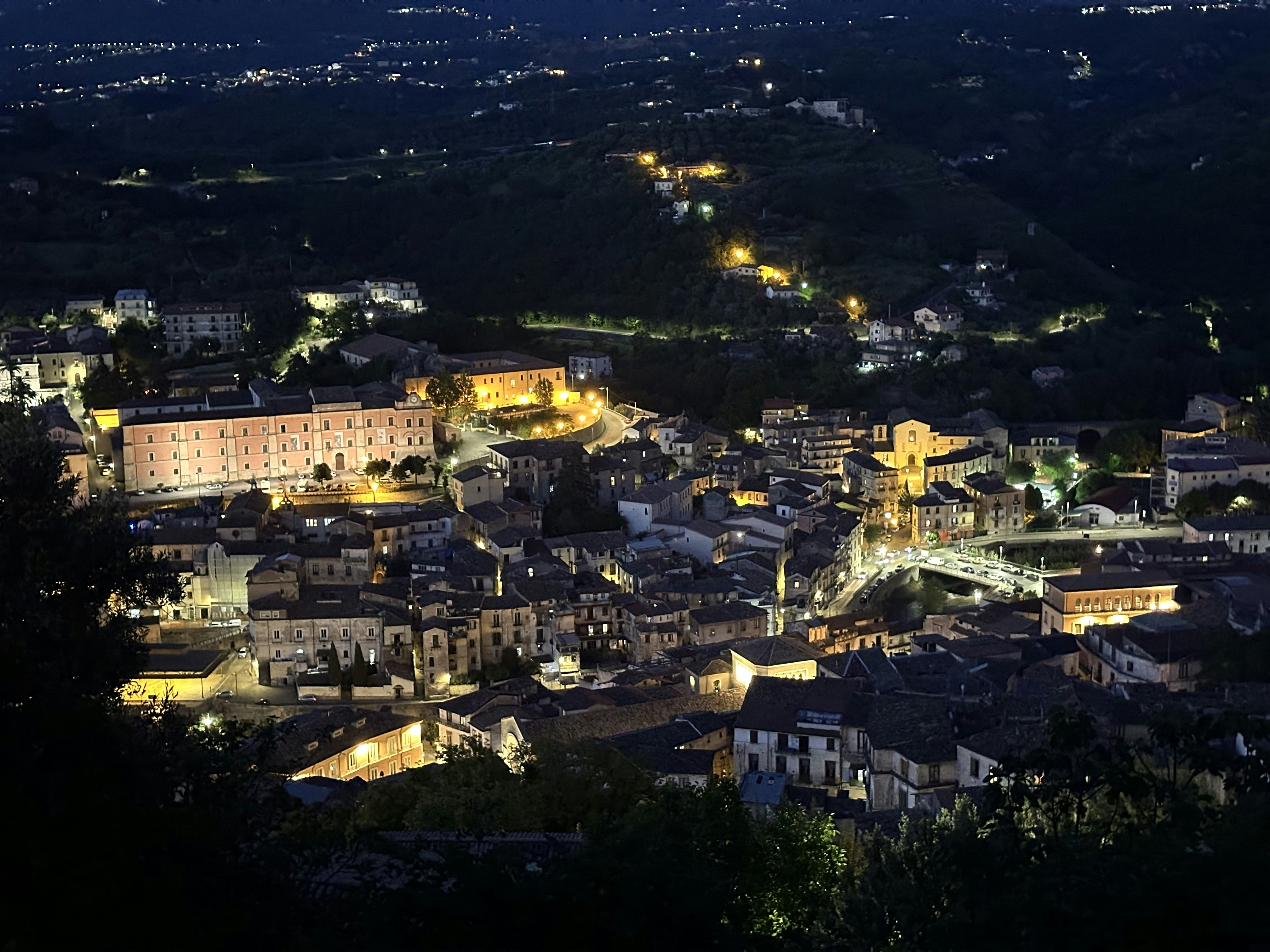 Nighttime hillside village: warm streets tracing a constellation of glow