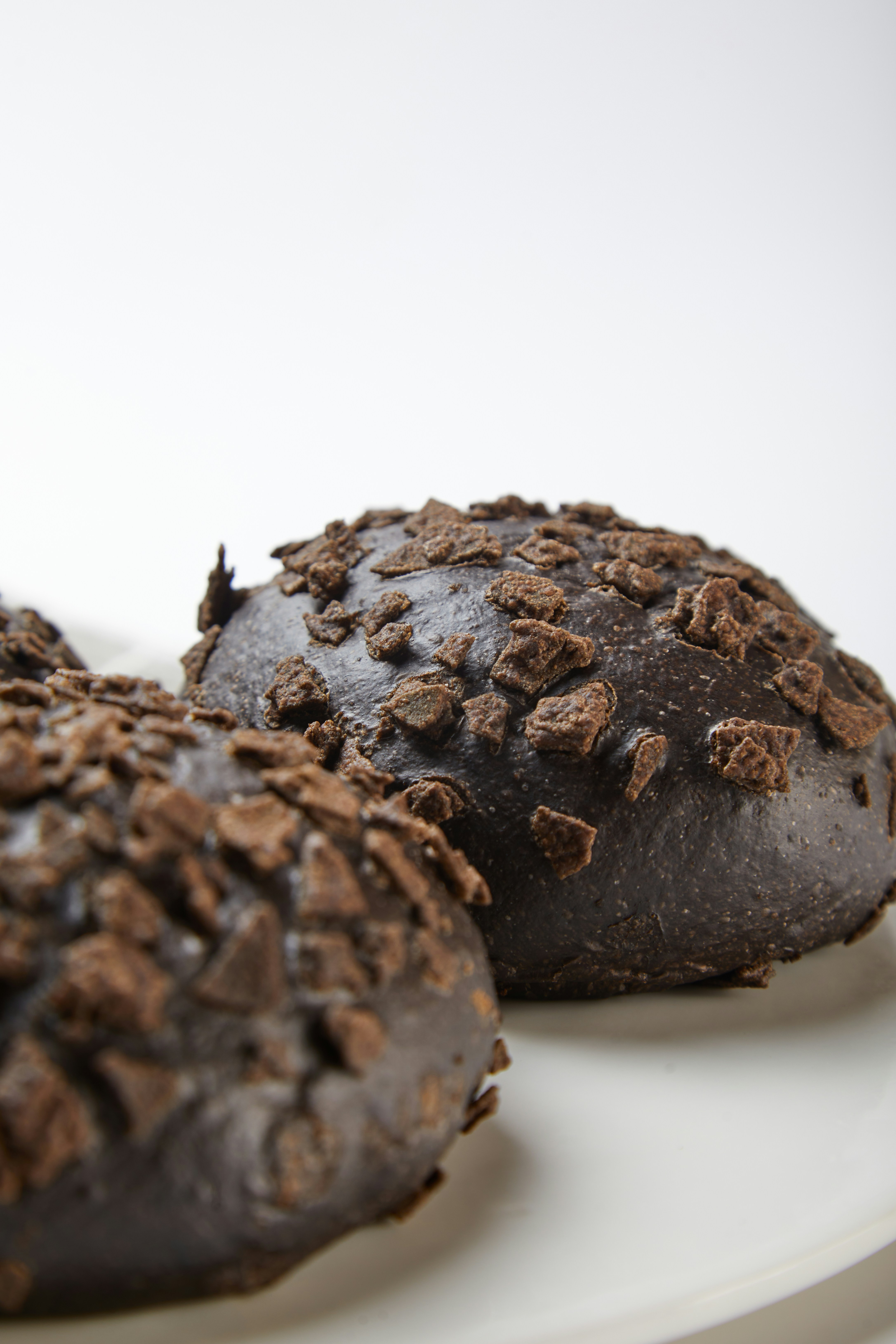 Chocolate-dusted donuts on a white plate, up close
