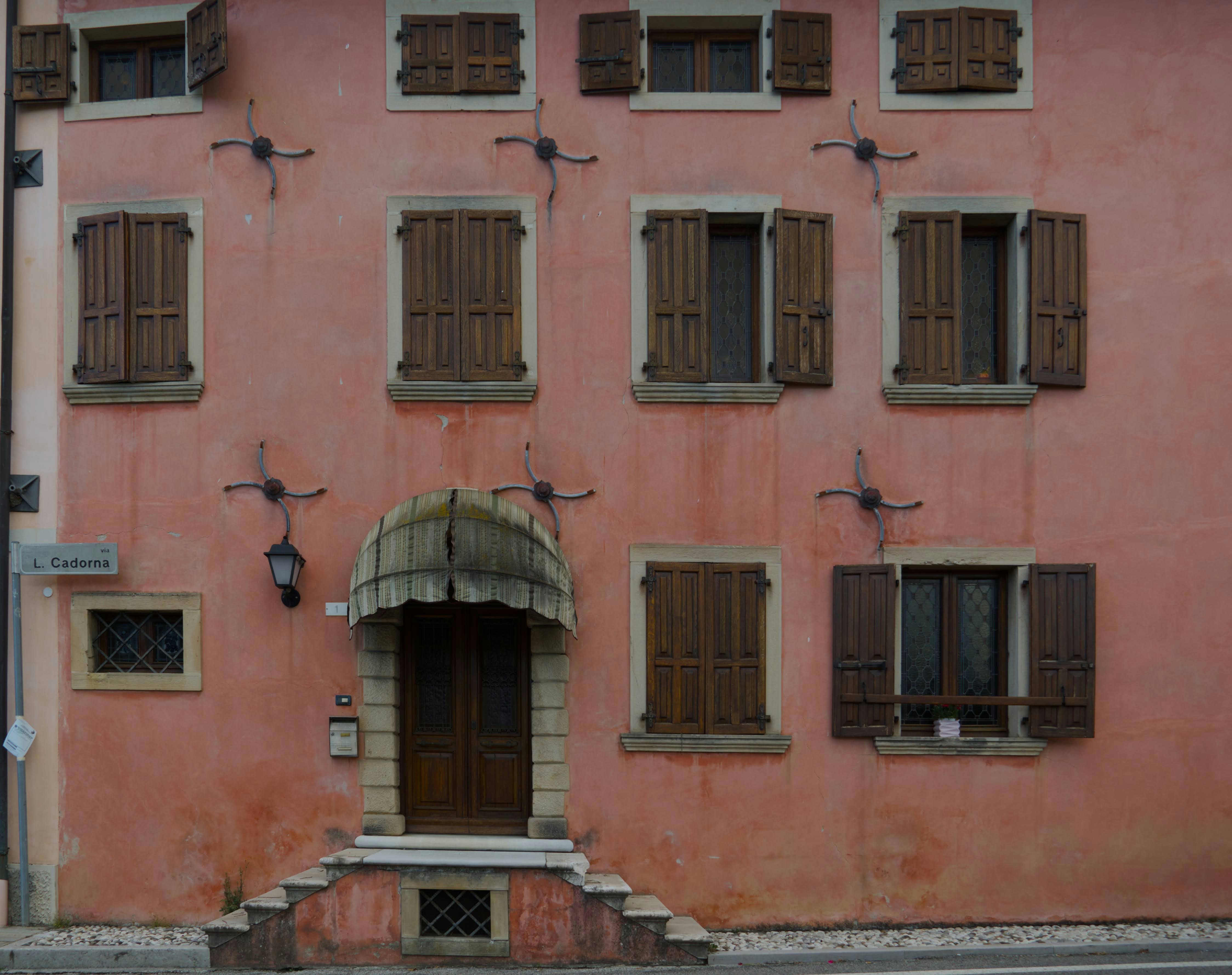 Weathered Pink Facade with Shuttered Windows and Stone Entrance