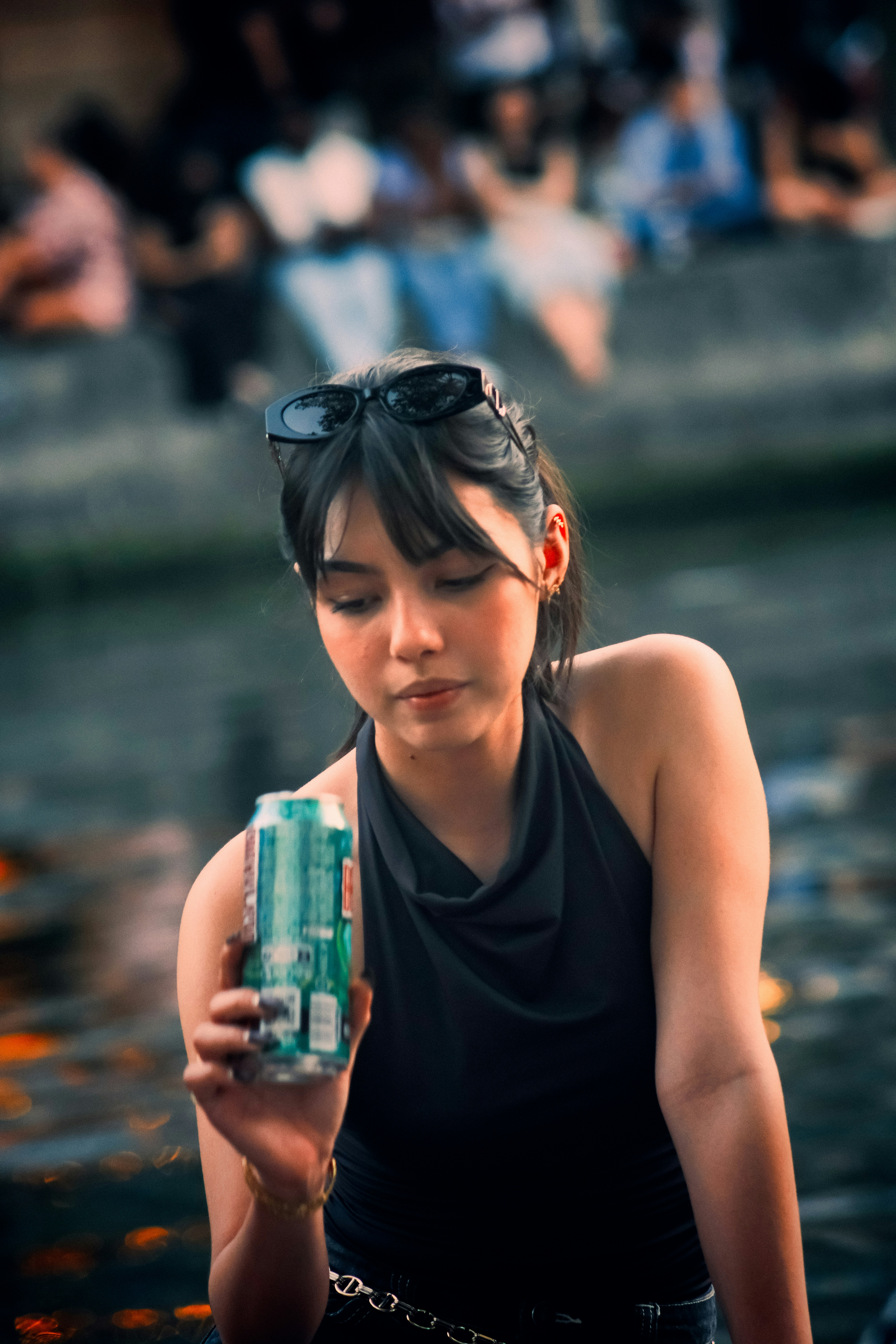 A young woman holding a drink can outdoors.