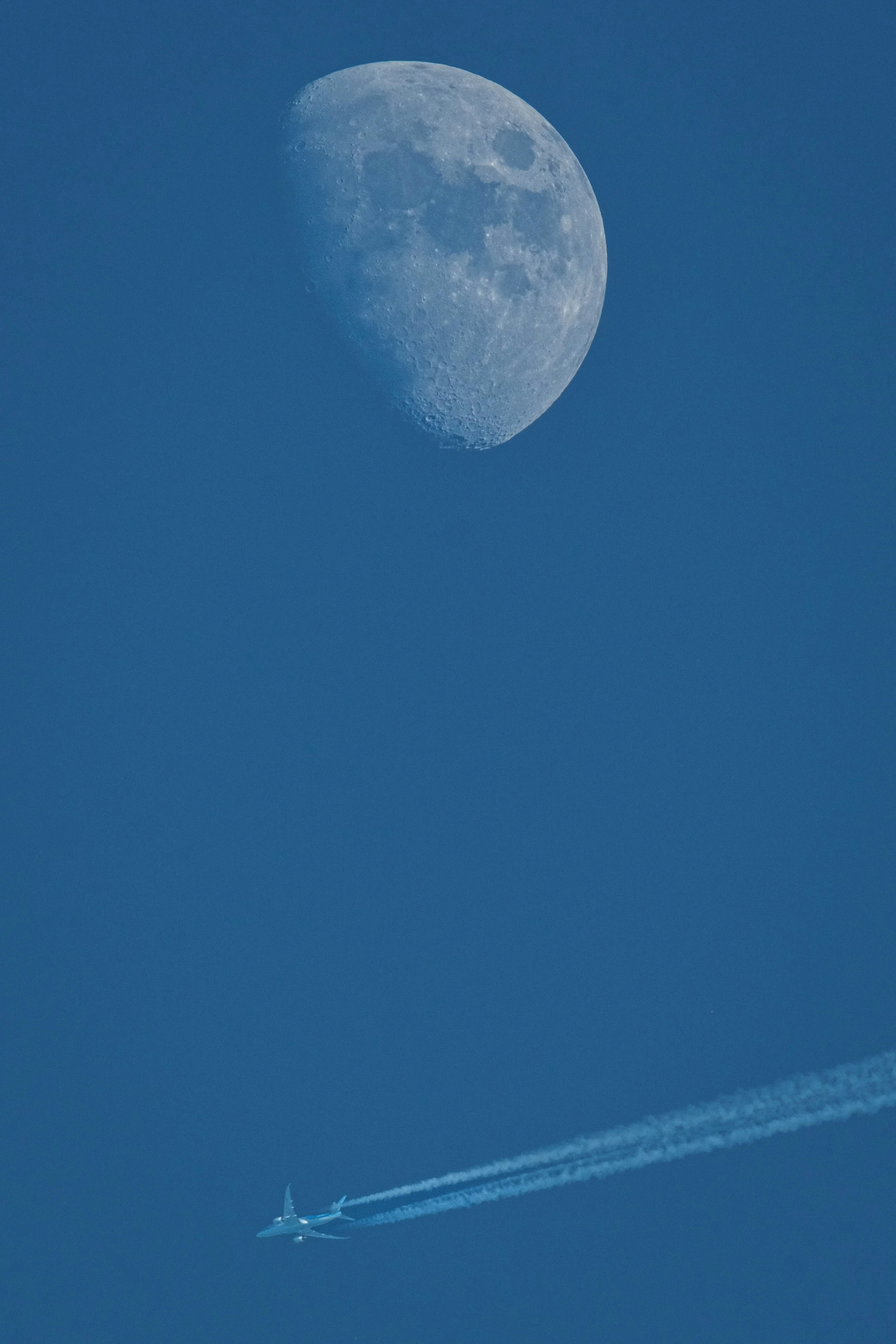 High-Altitude Traces: Moon Over a Jet Linethrough Sky