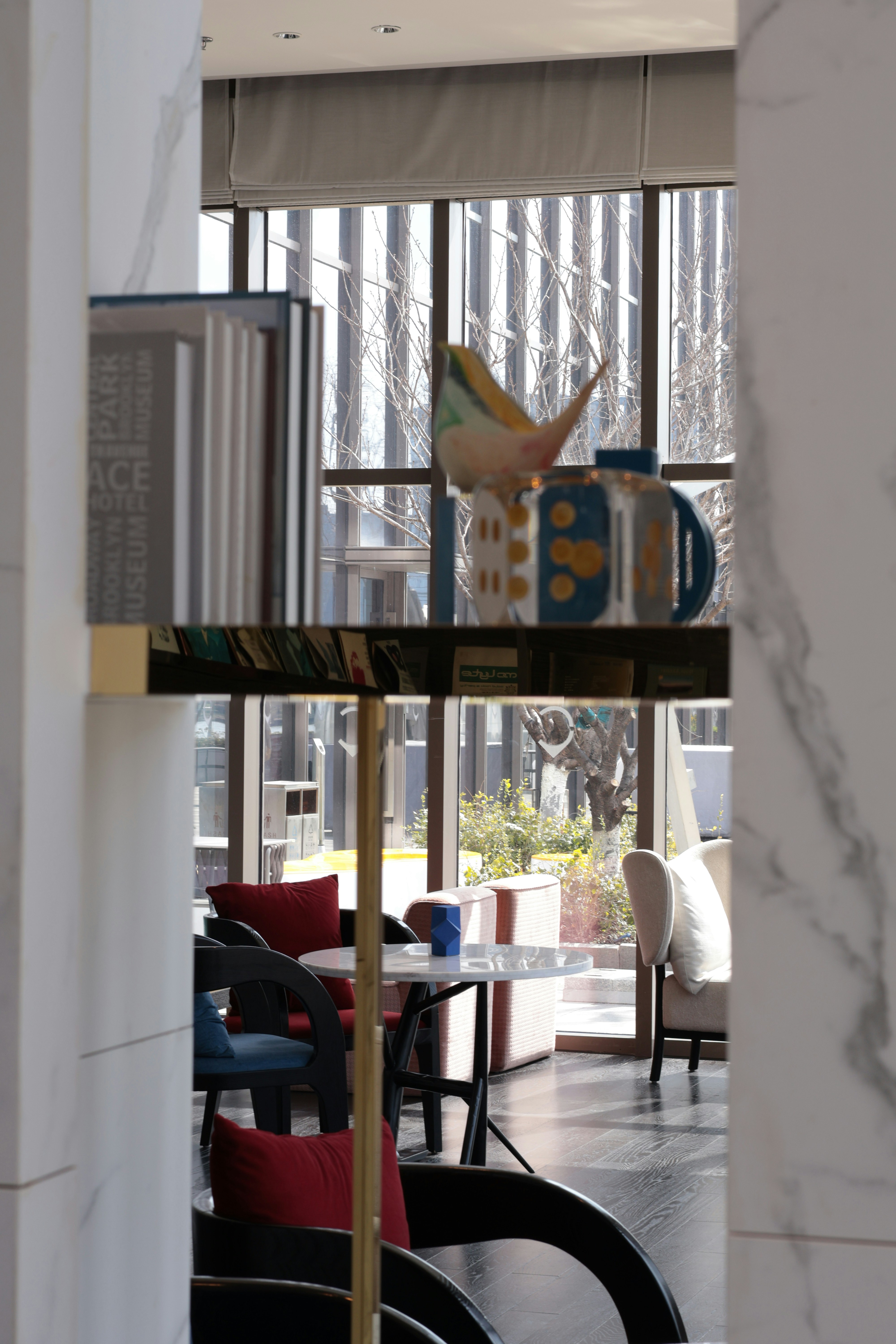 Interior cafe scene with ceramic bird and cluttered shelf on sunlit glass-walled backdrop
