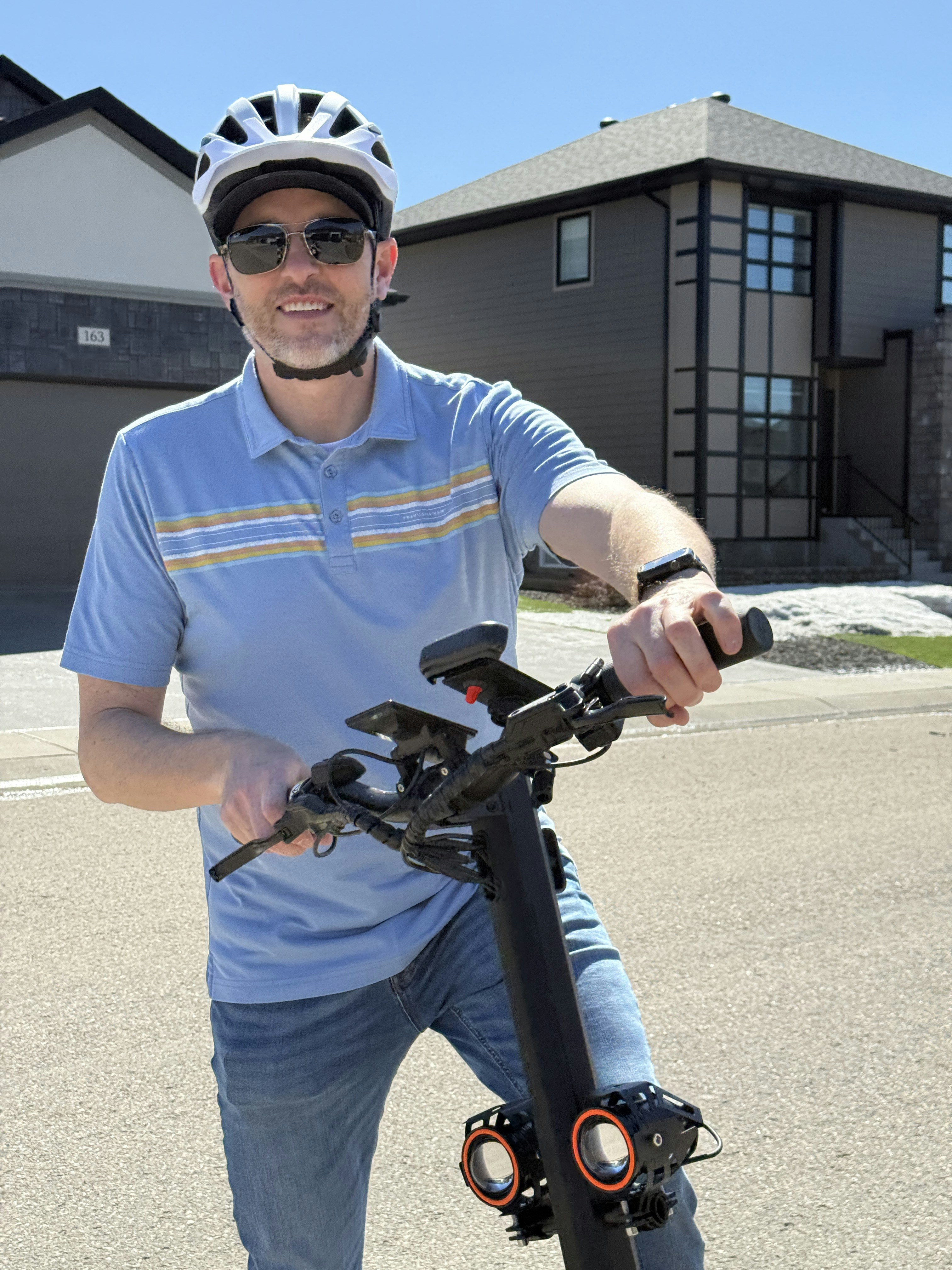 Cyclist on a sunny suburban street with a mounted e-scooter