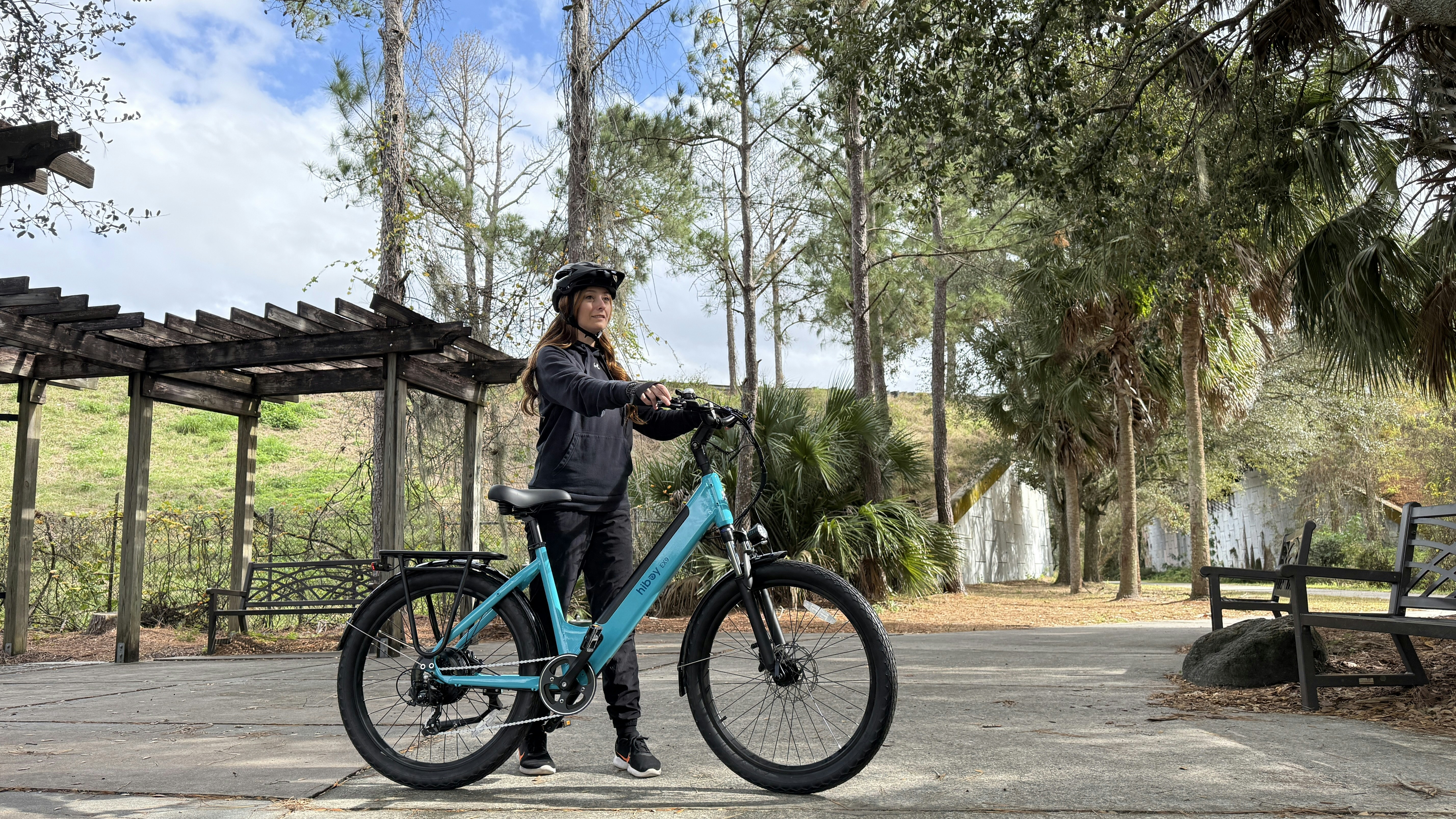 Rider in teal e-bike poised beside a shaded park