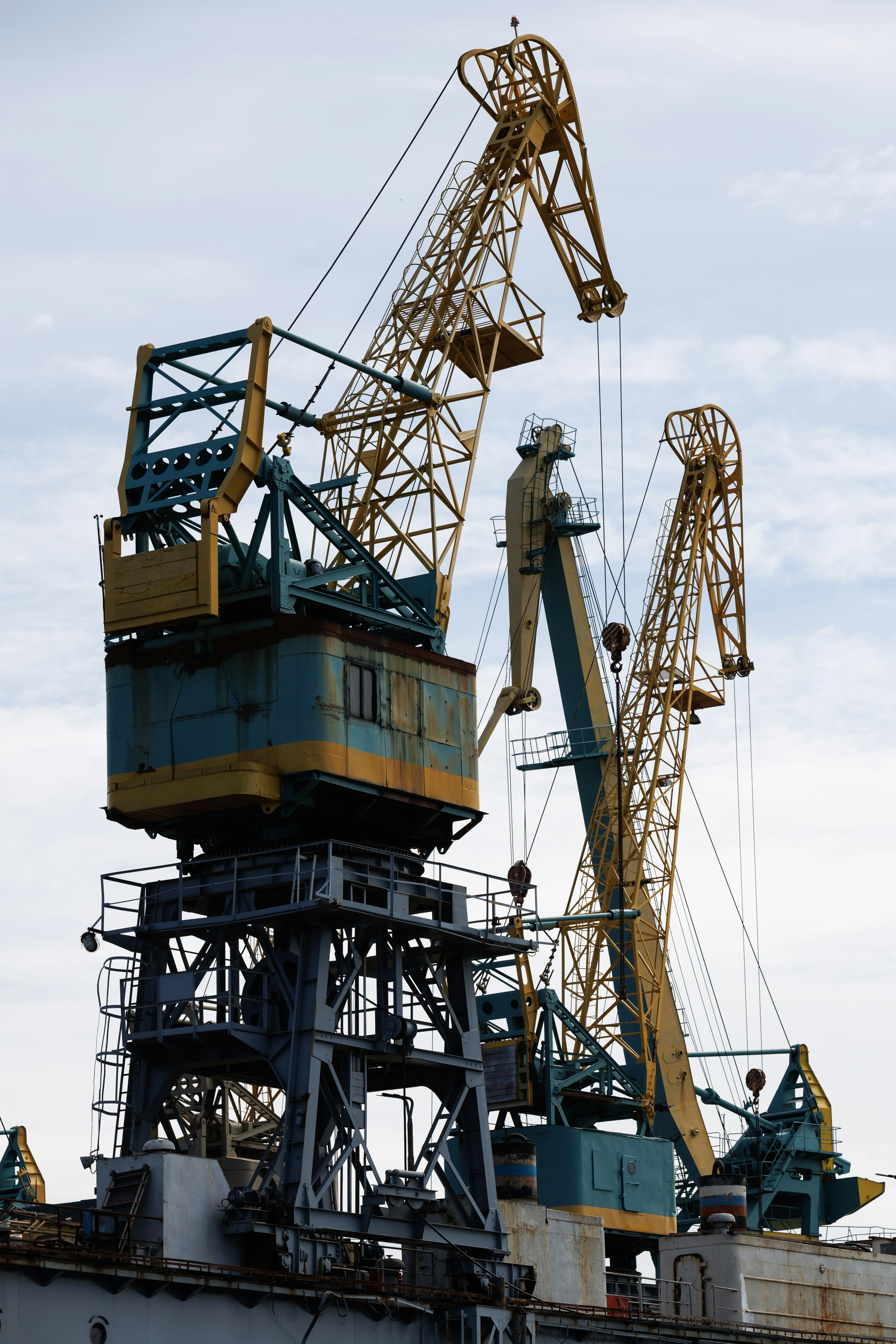 Large industrial cranes stand tall against a cloudy sky.