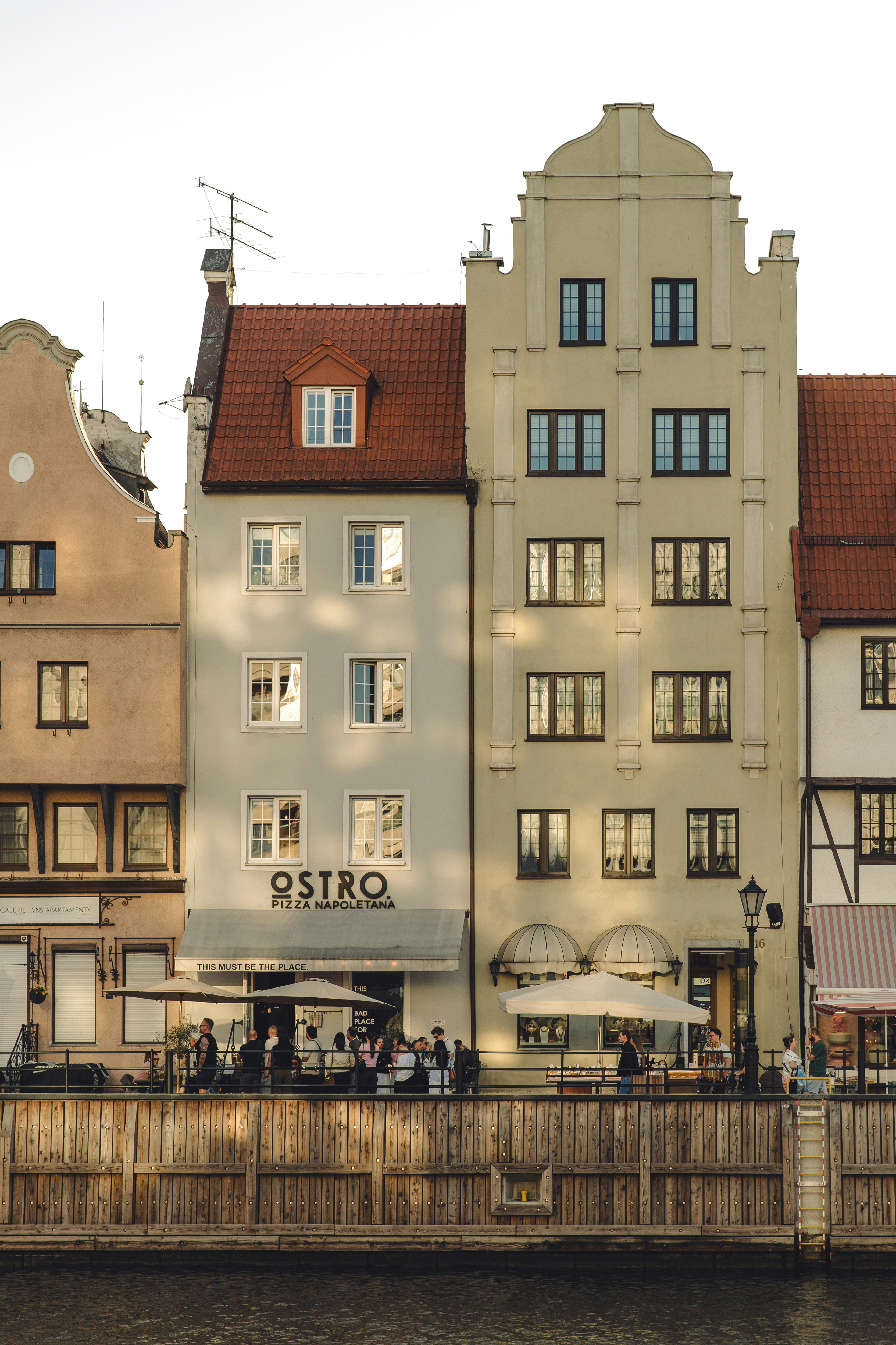 Sunny riverside row of European townhouses with restaurant terrace