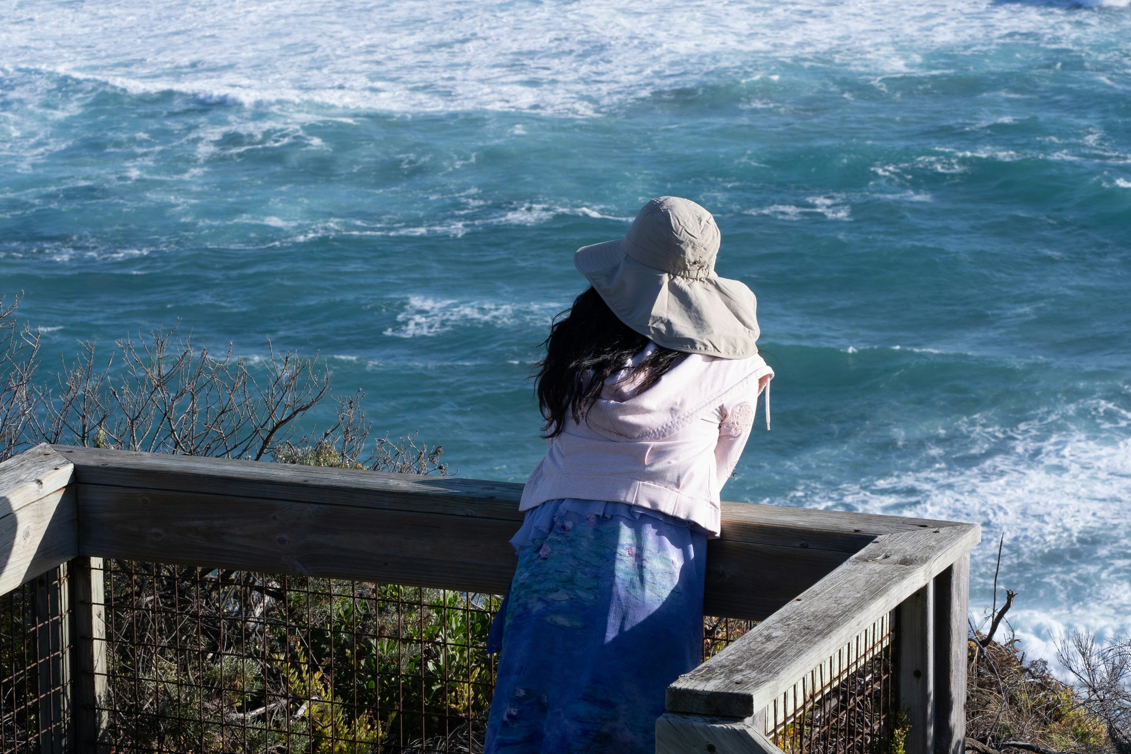 Rear-view Hangout: A figure gazes toward the restless sea from a wooden overlook