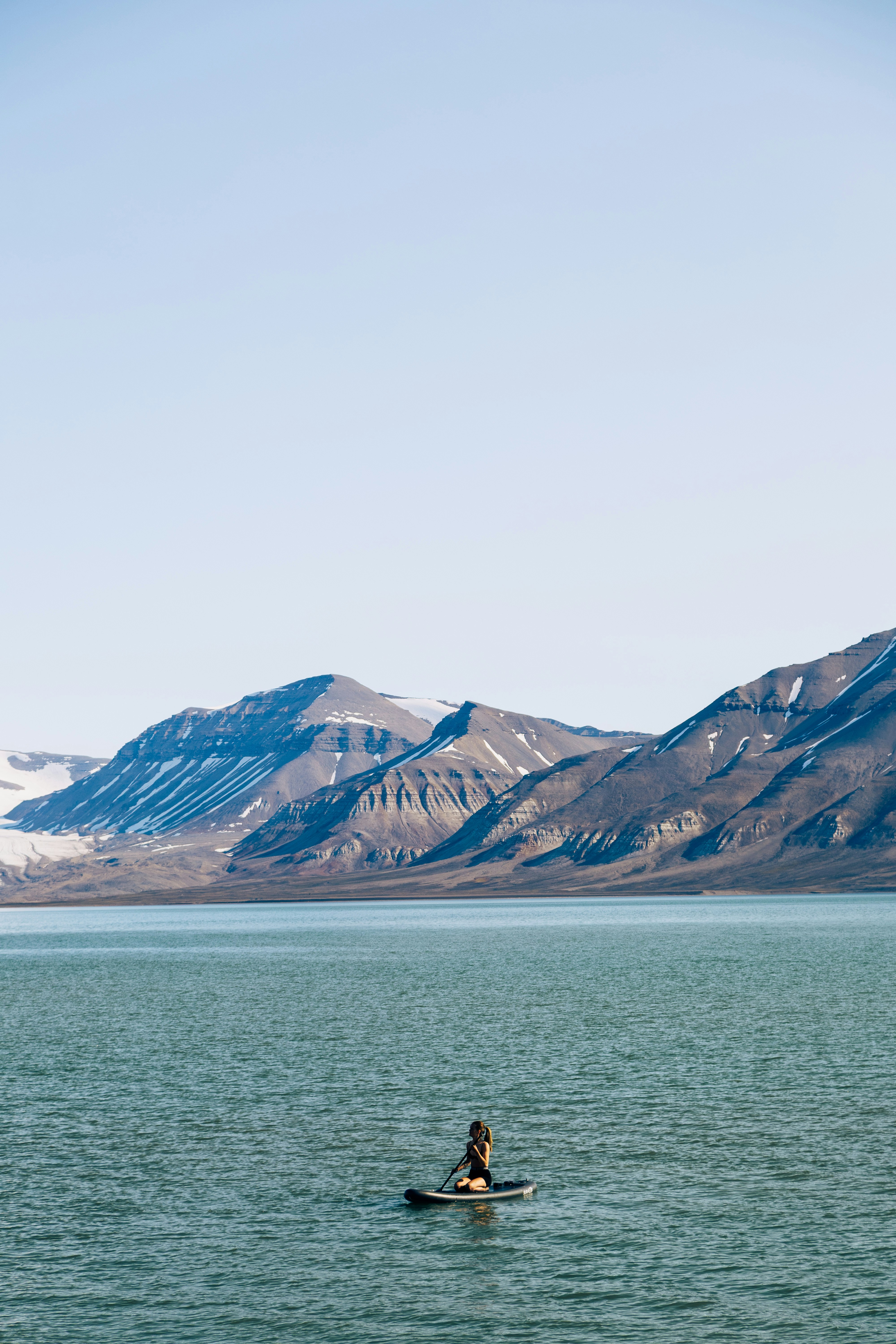 Serene Stand: lone paddler amid a glacier-fed lake under vast blue skies
