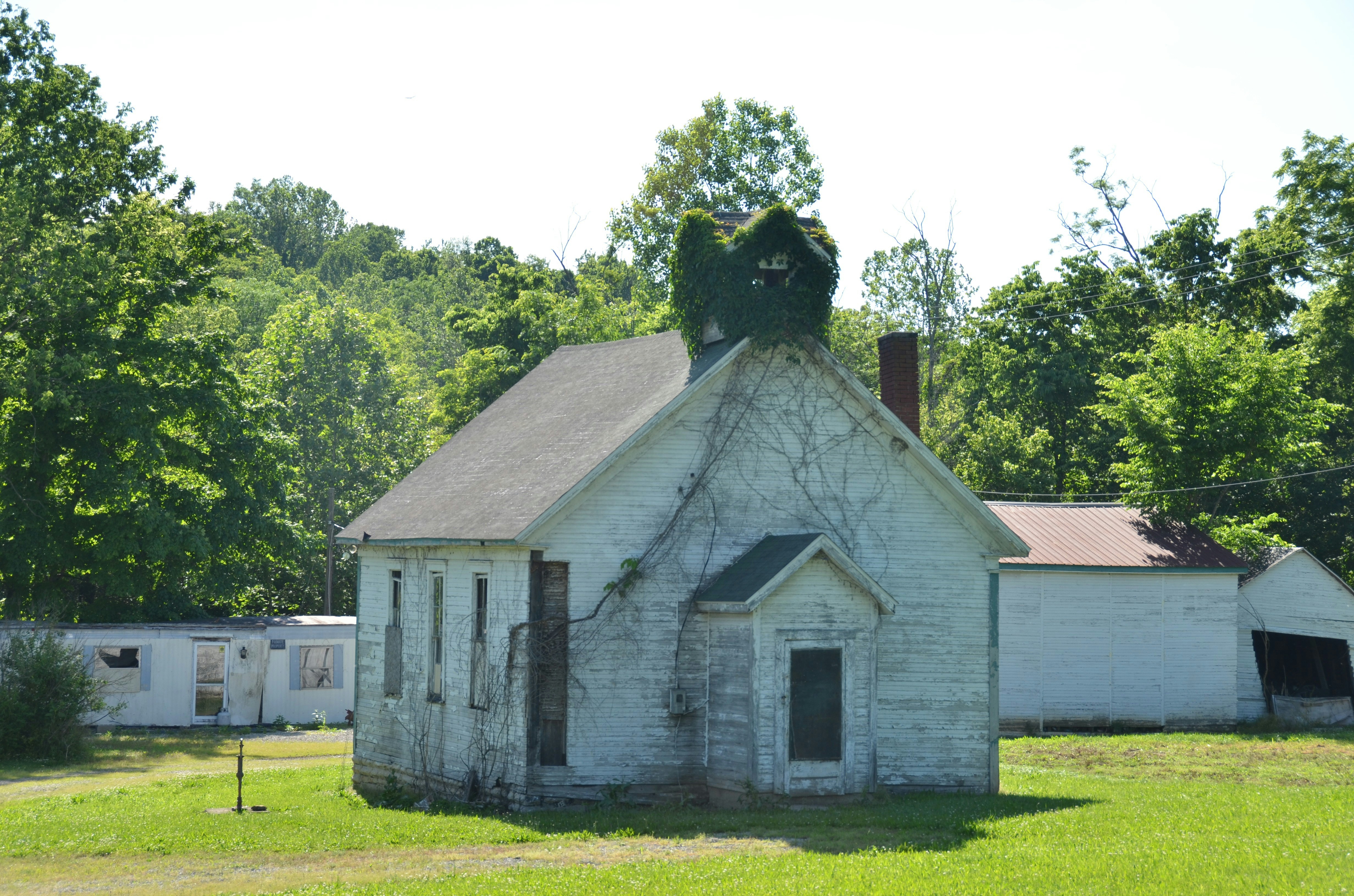 Weathered White Chapel: Ivy-Wrapped Gable Among Quiet Fields
