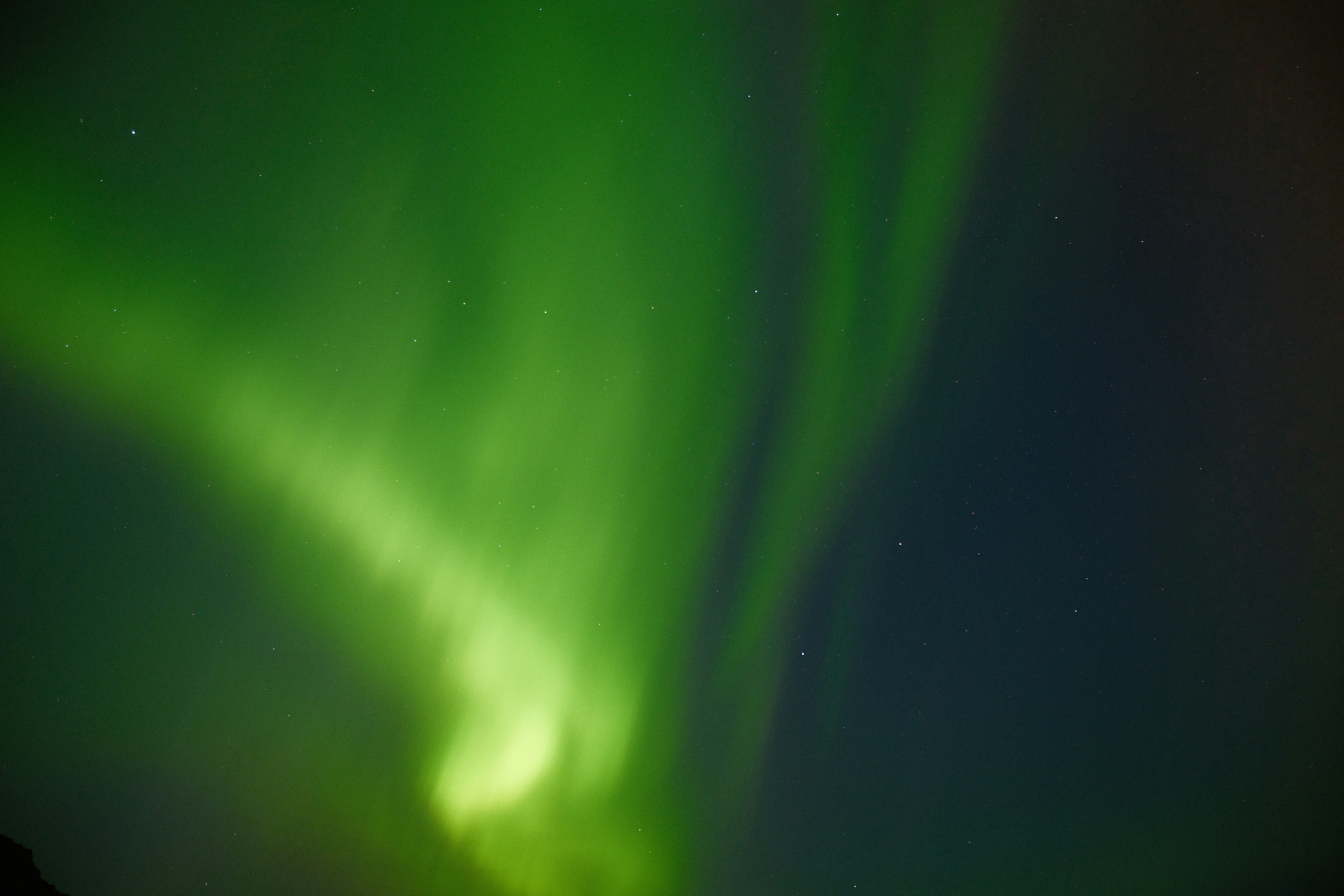 Vibrant green aurora borealis lights up the dark night sky.