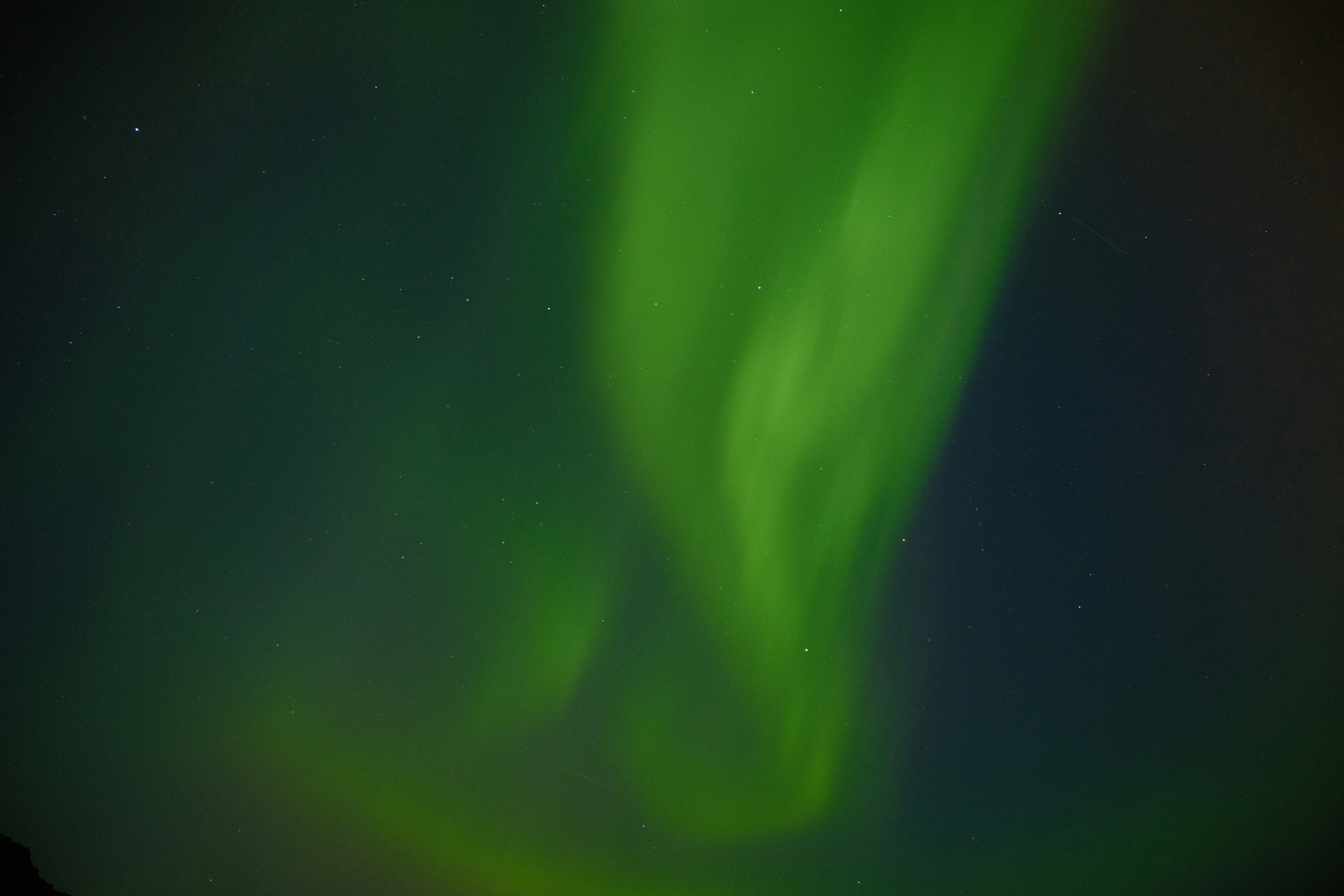 Emerald Veil: Northern Lights Curl Over a Quiet Twilight Landscape