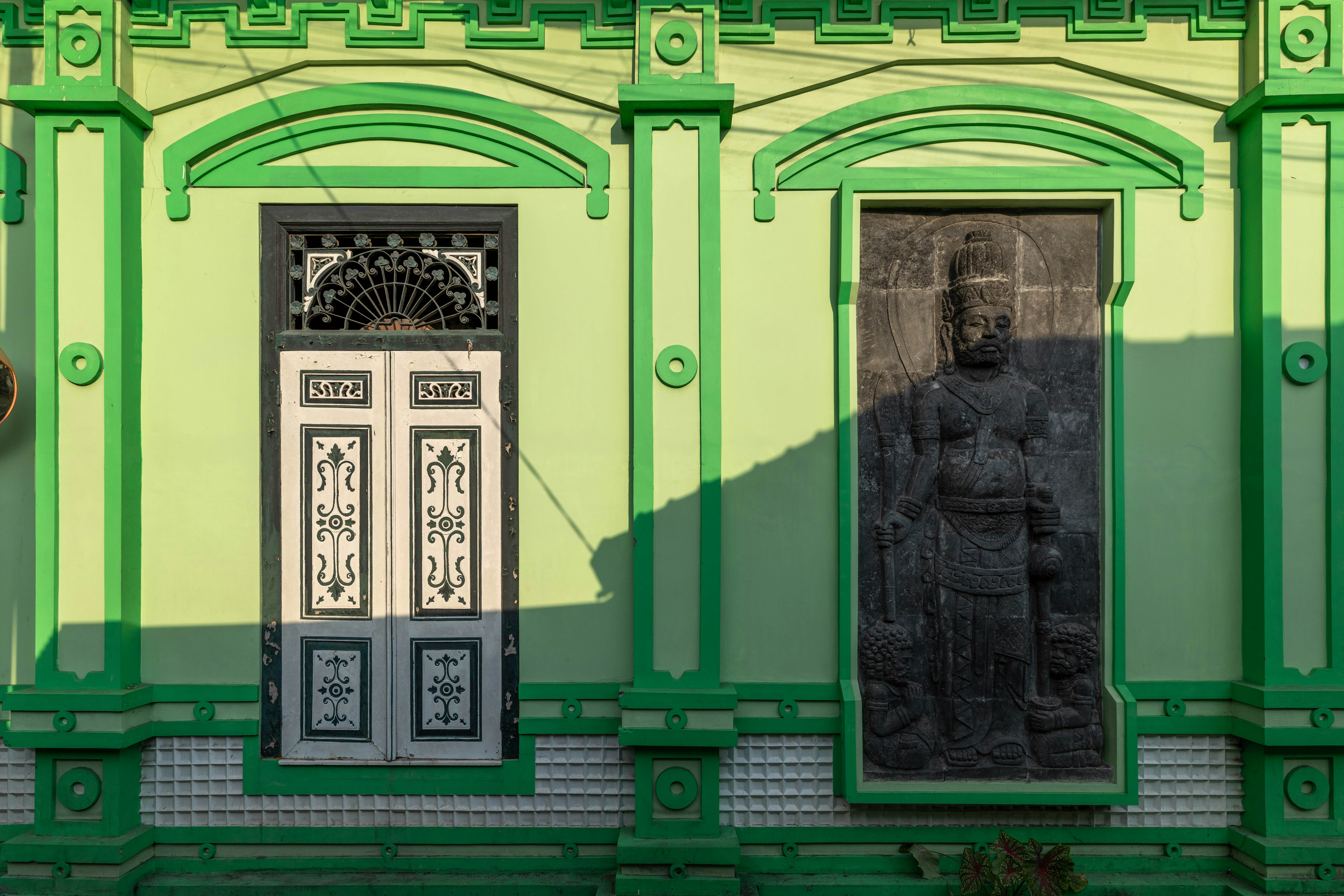 Green Facade Portrait: A Classical Door and a Shadowed Warrior