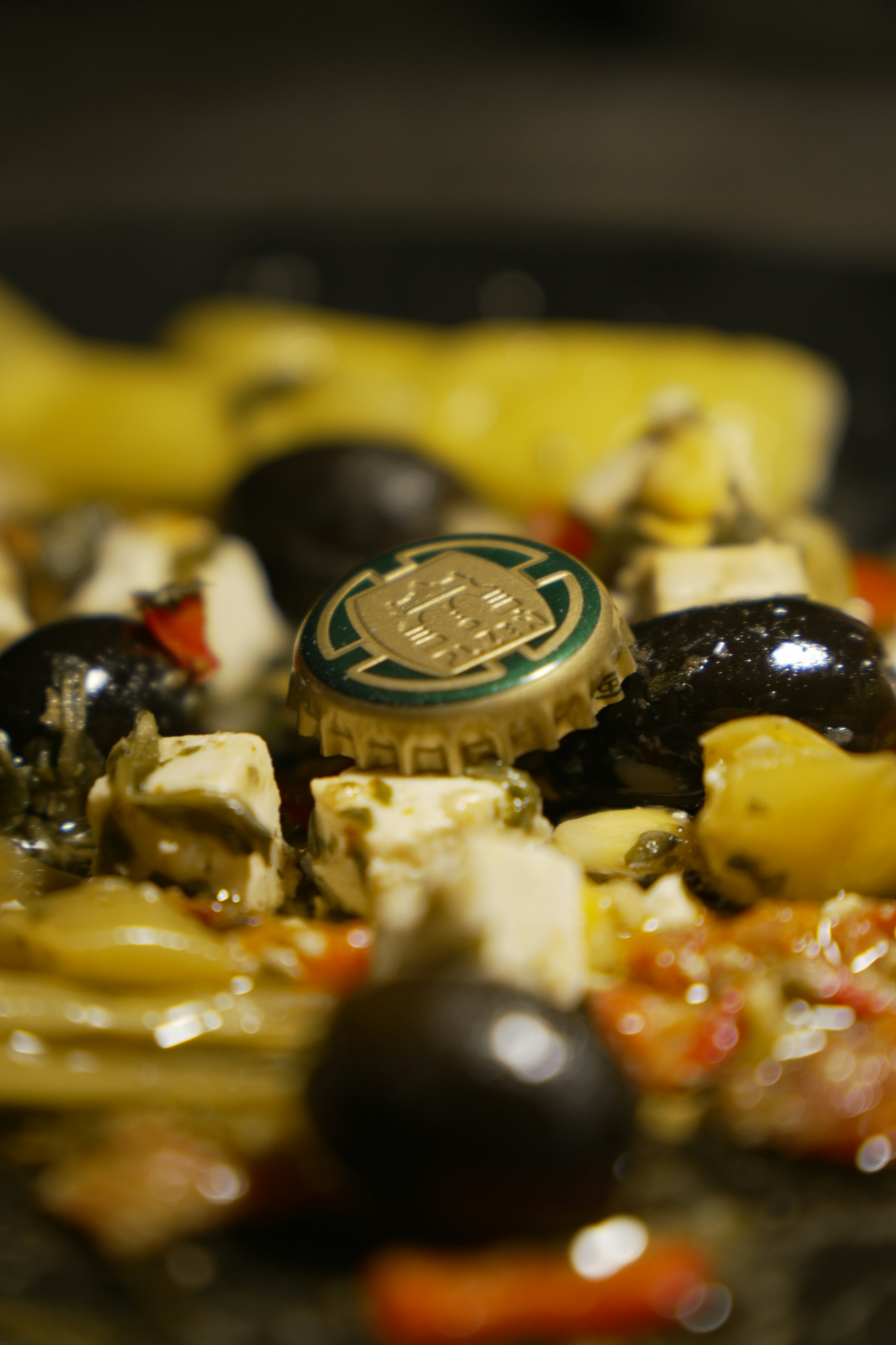 Olives, feta, and peppers with a bottle cap in oil.