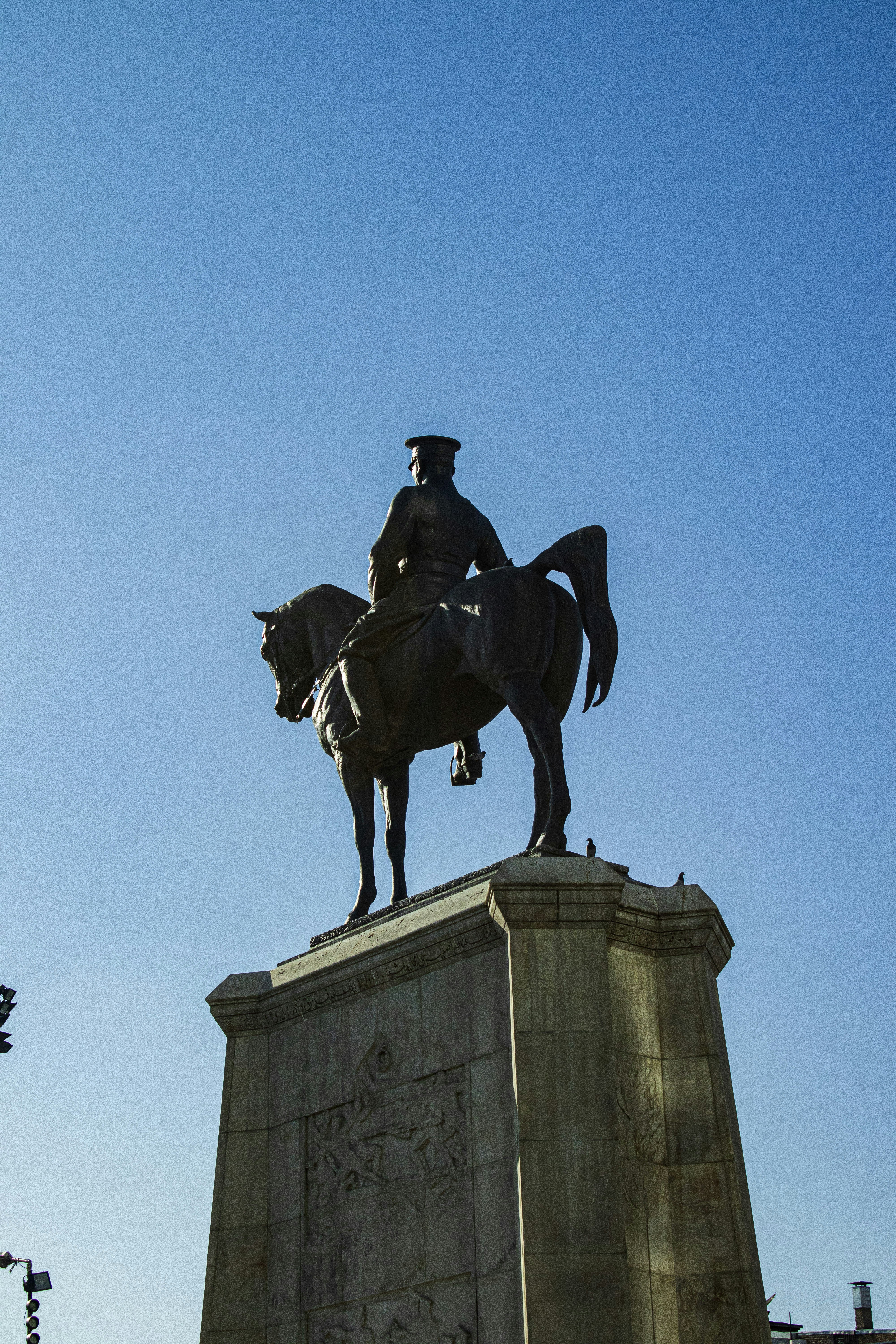 Equestrian Colossus: A Rider Silhouetted Against a Clear Blue Sky