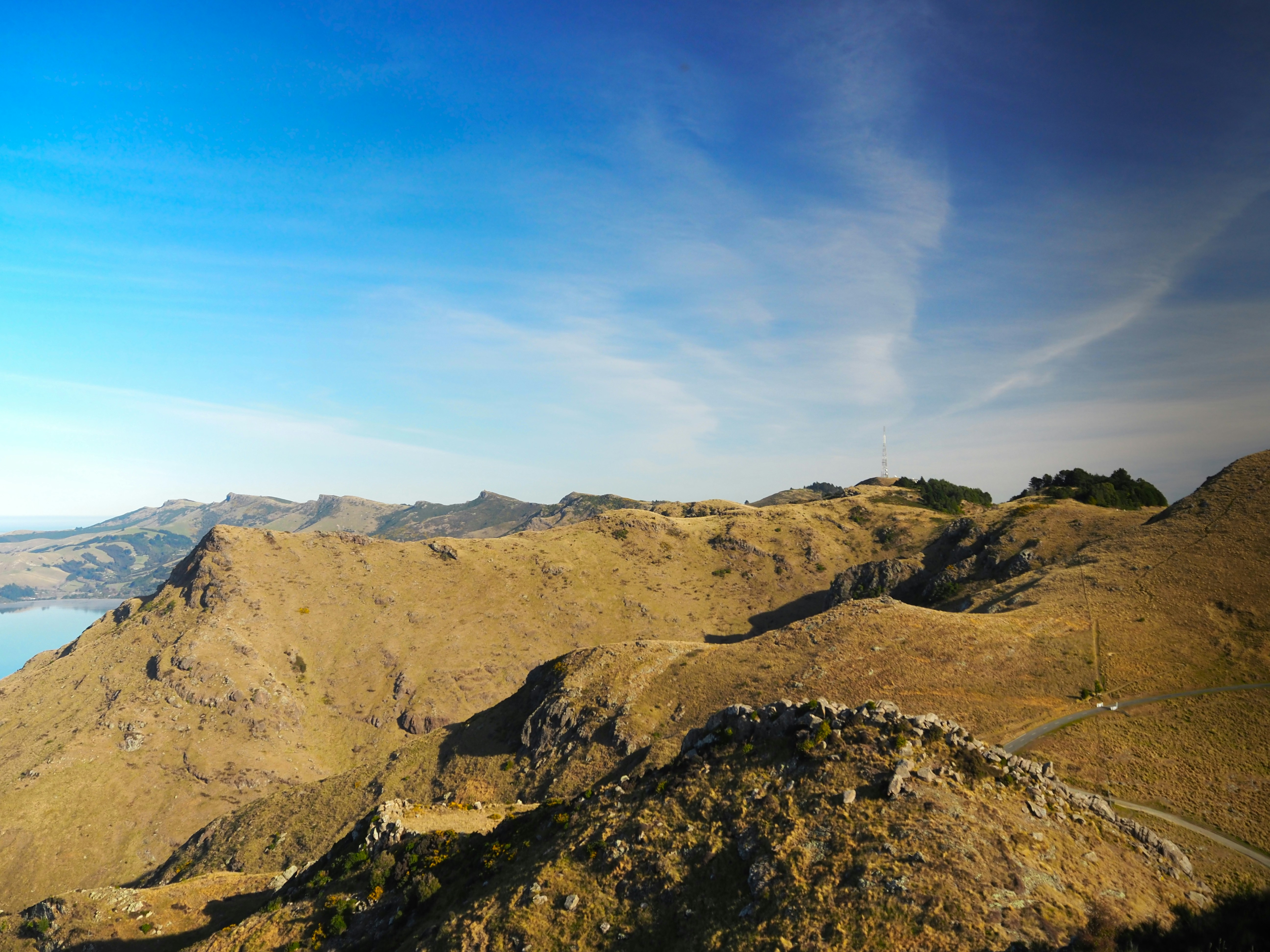 Clifftop Path Over Golden Hills Beneath a Brilliant Sky