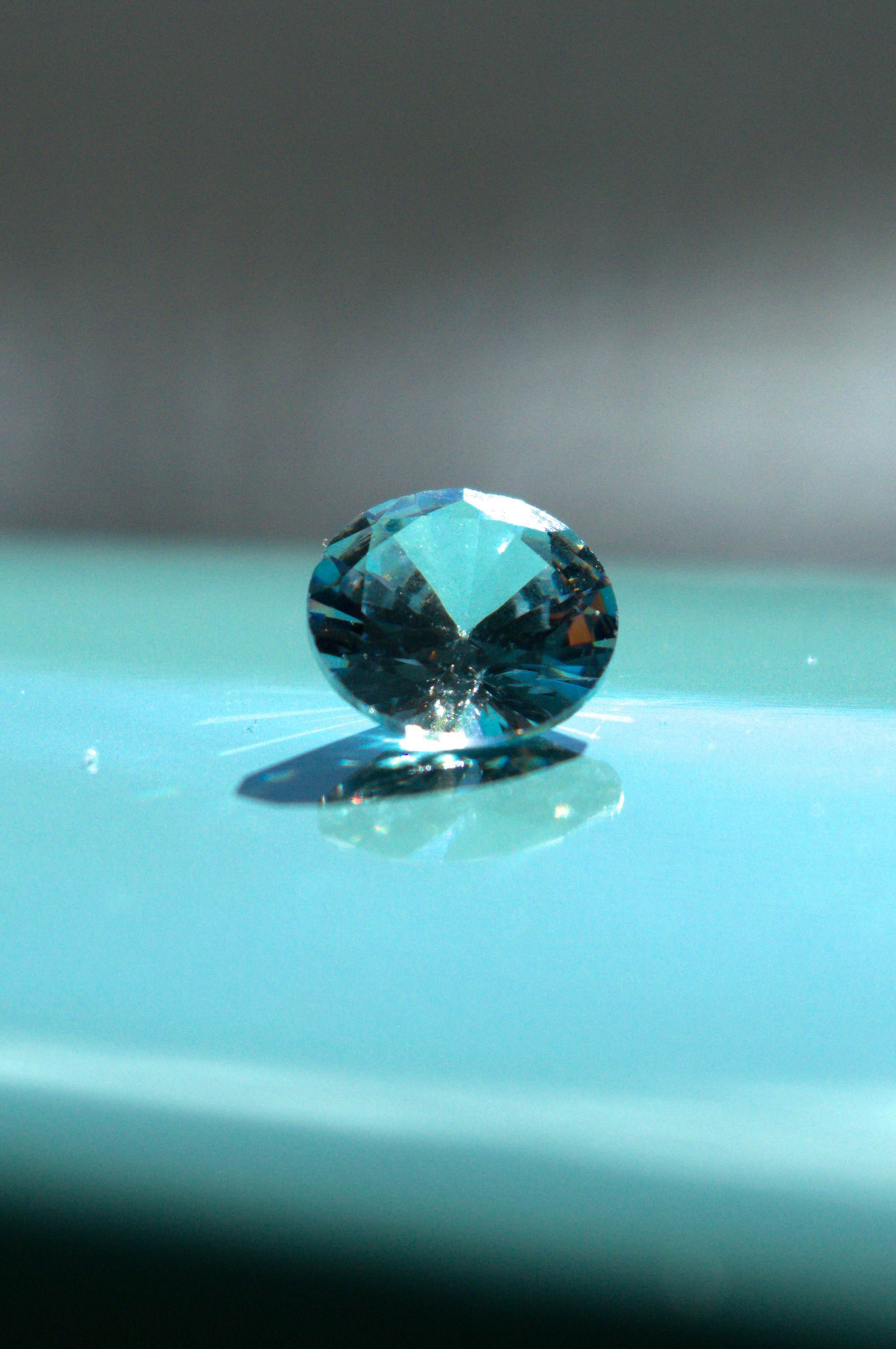 A Teal Gem Resting on Glass: Prismed Light and Quiet Reflections