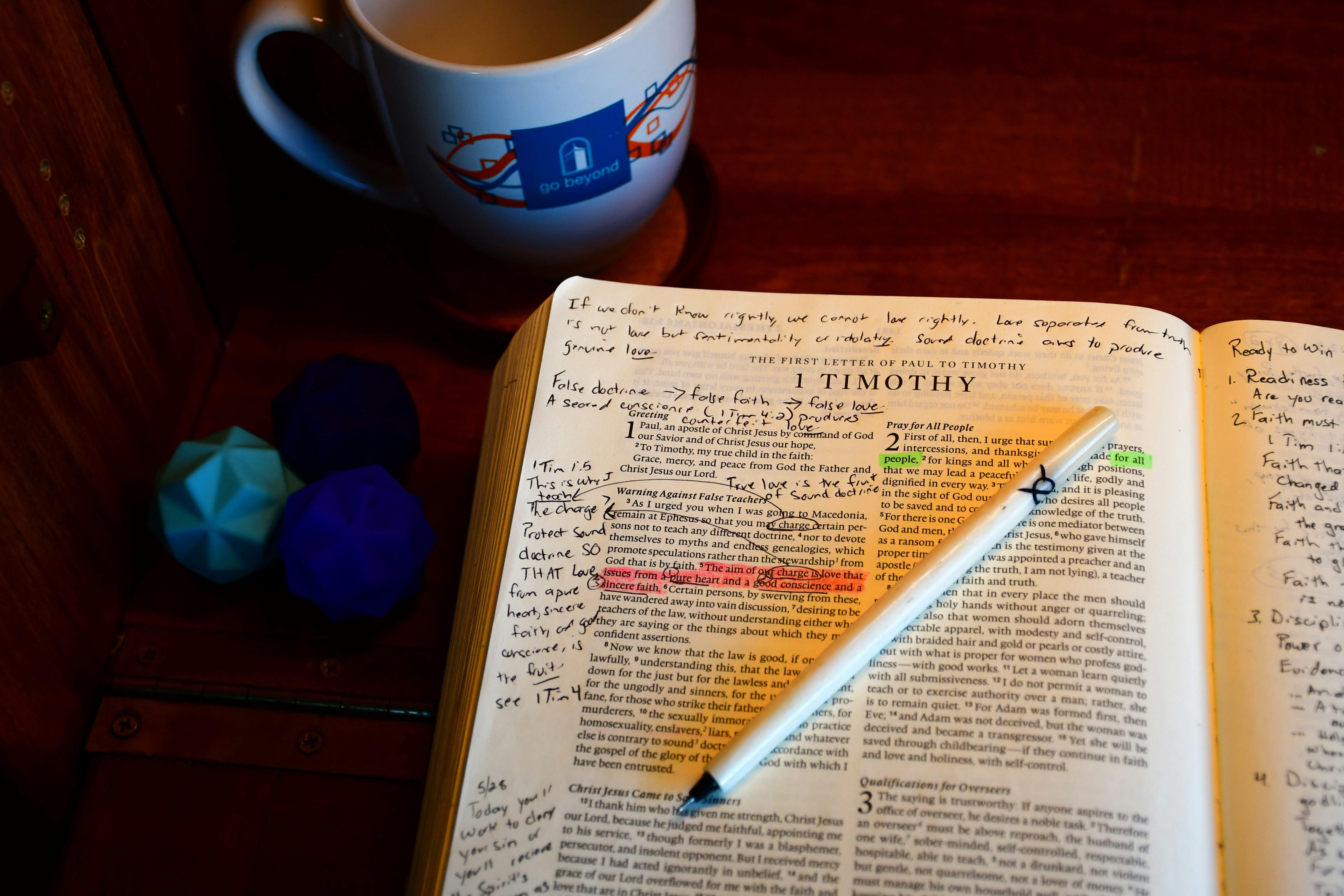 Pen resting on illuminated scripture beside a coffee mug