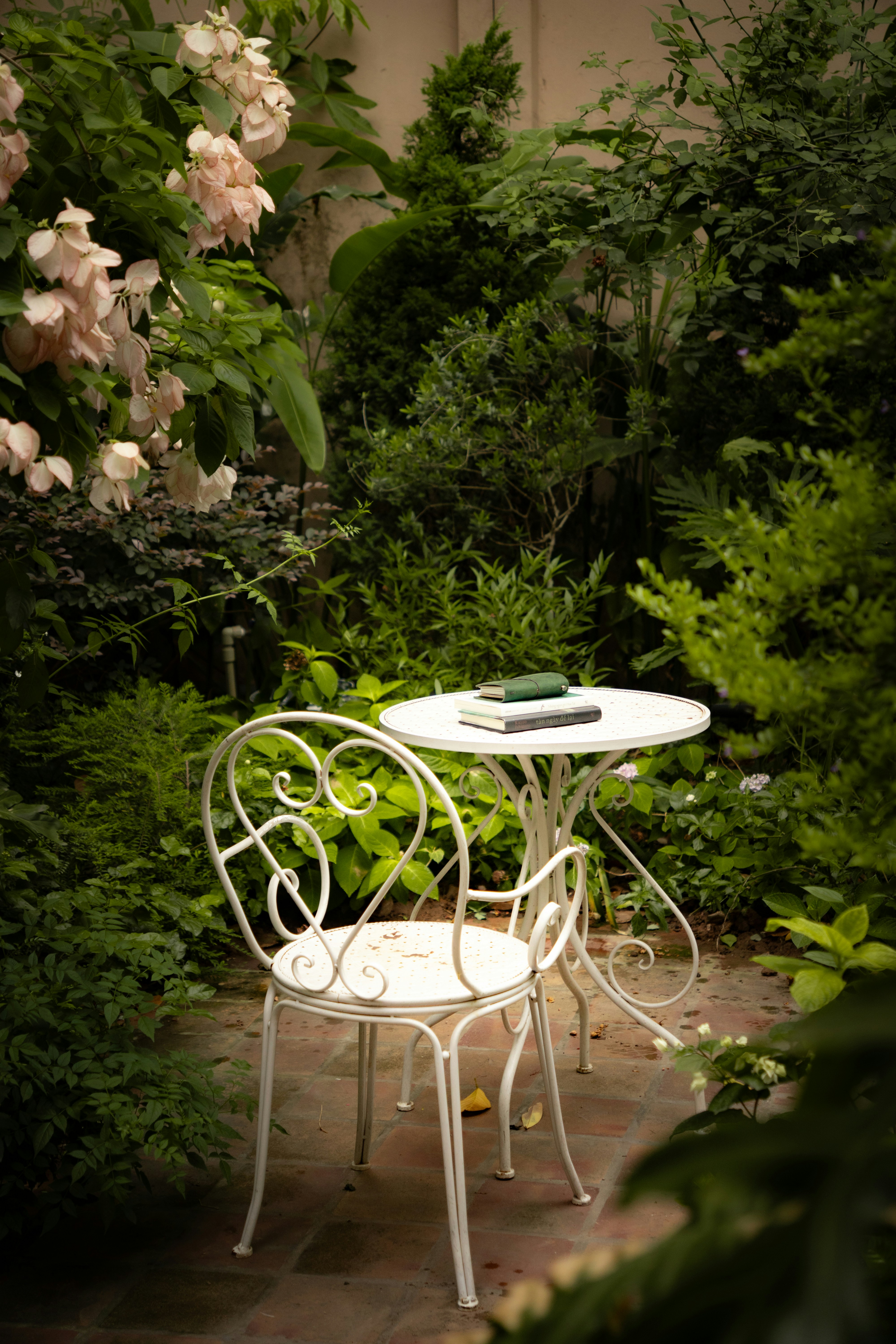 Garden Oasis: White wrought-iron Table Set Among Quiet Greenery
