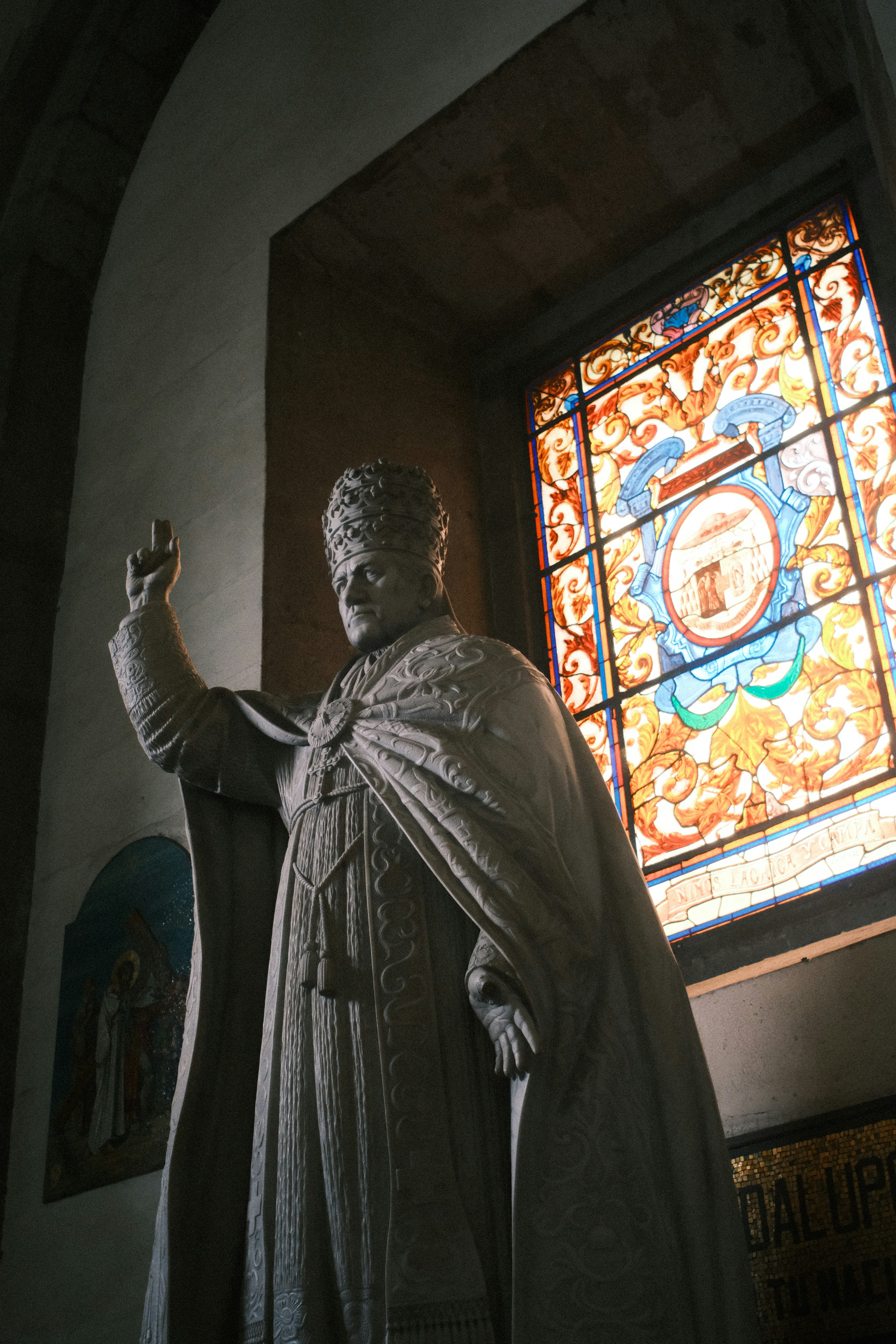 The Regal Sentinel: Statue Beneath Stained Glass