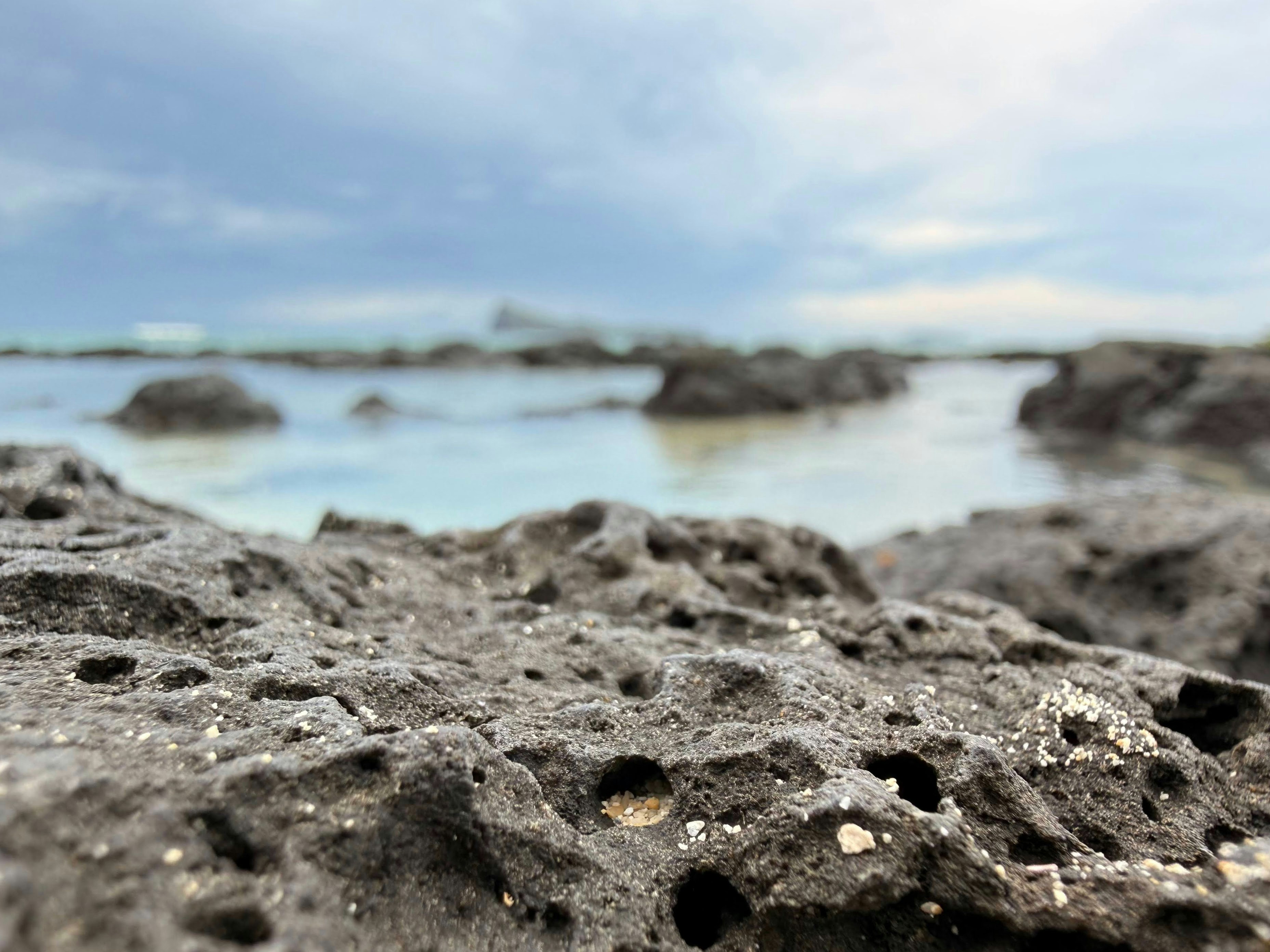 Textured Coastal Grotto: Weathered Rocks Meet a Quiet Sea
