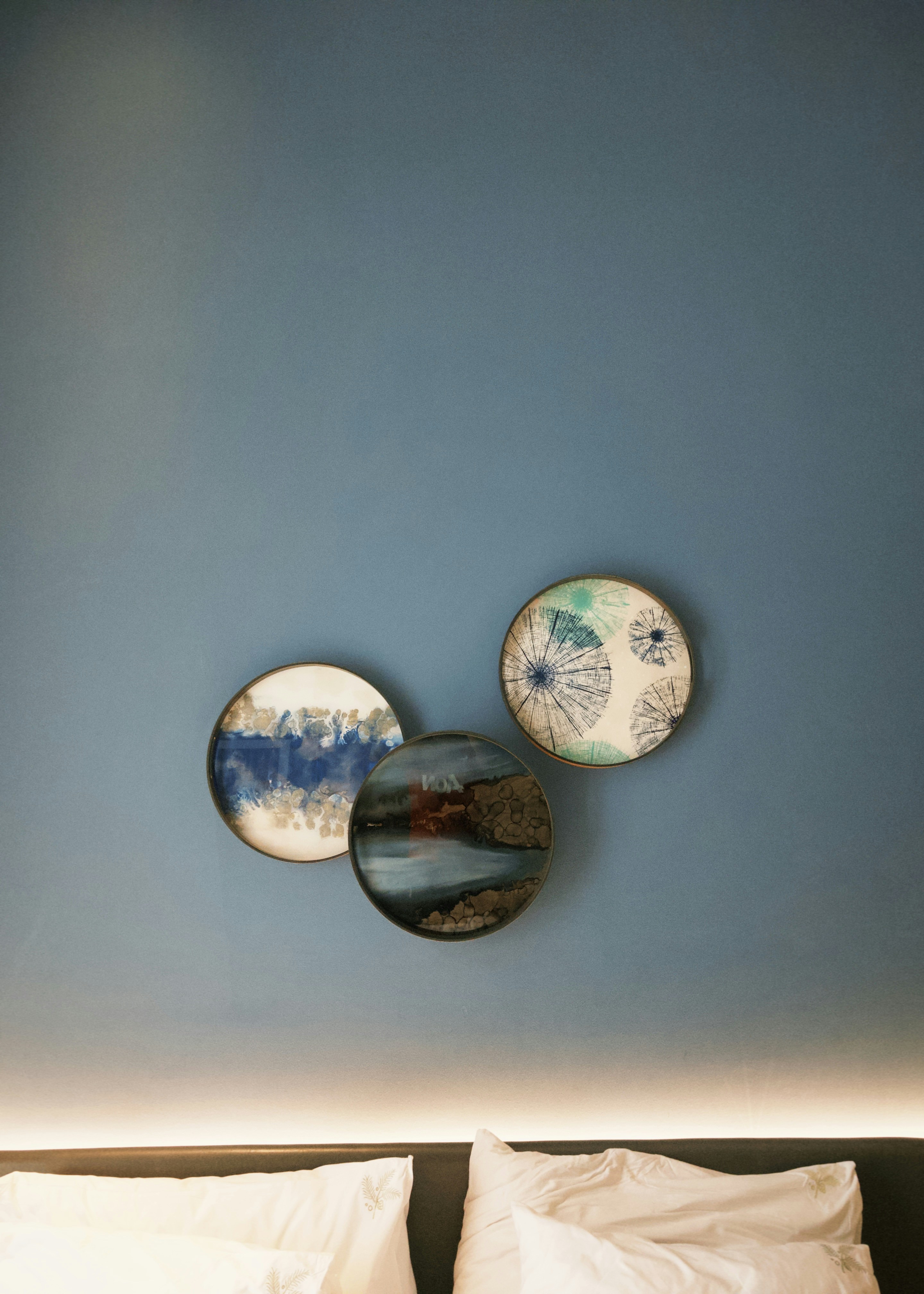 Three round wall sculptures drift above a pastel blue wall