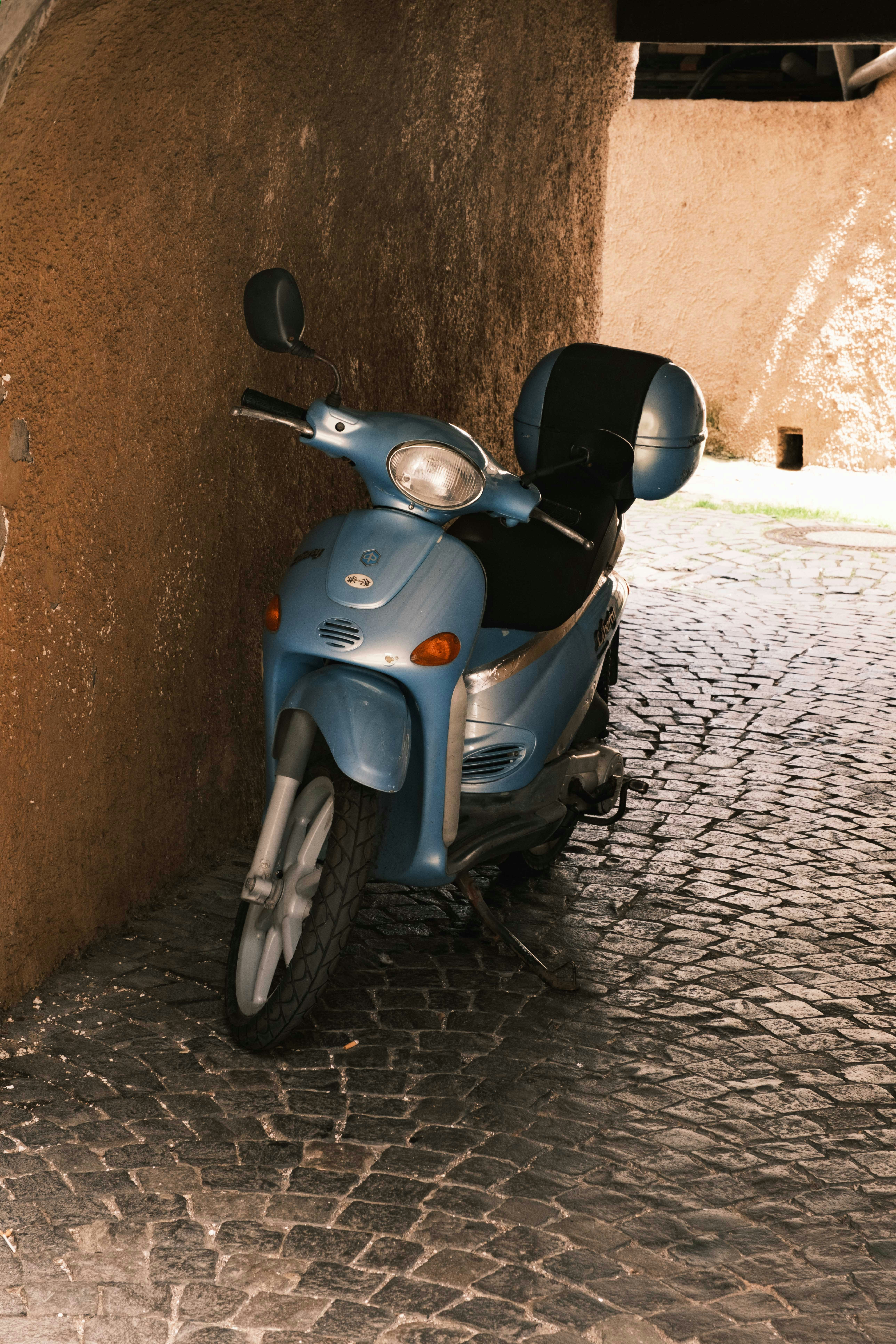 Blue Scooter Nestled in a Cobblestone Alley