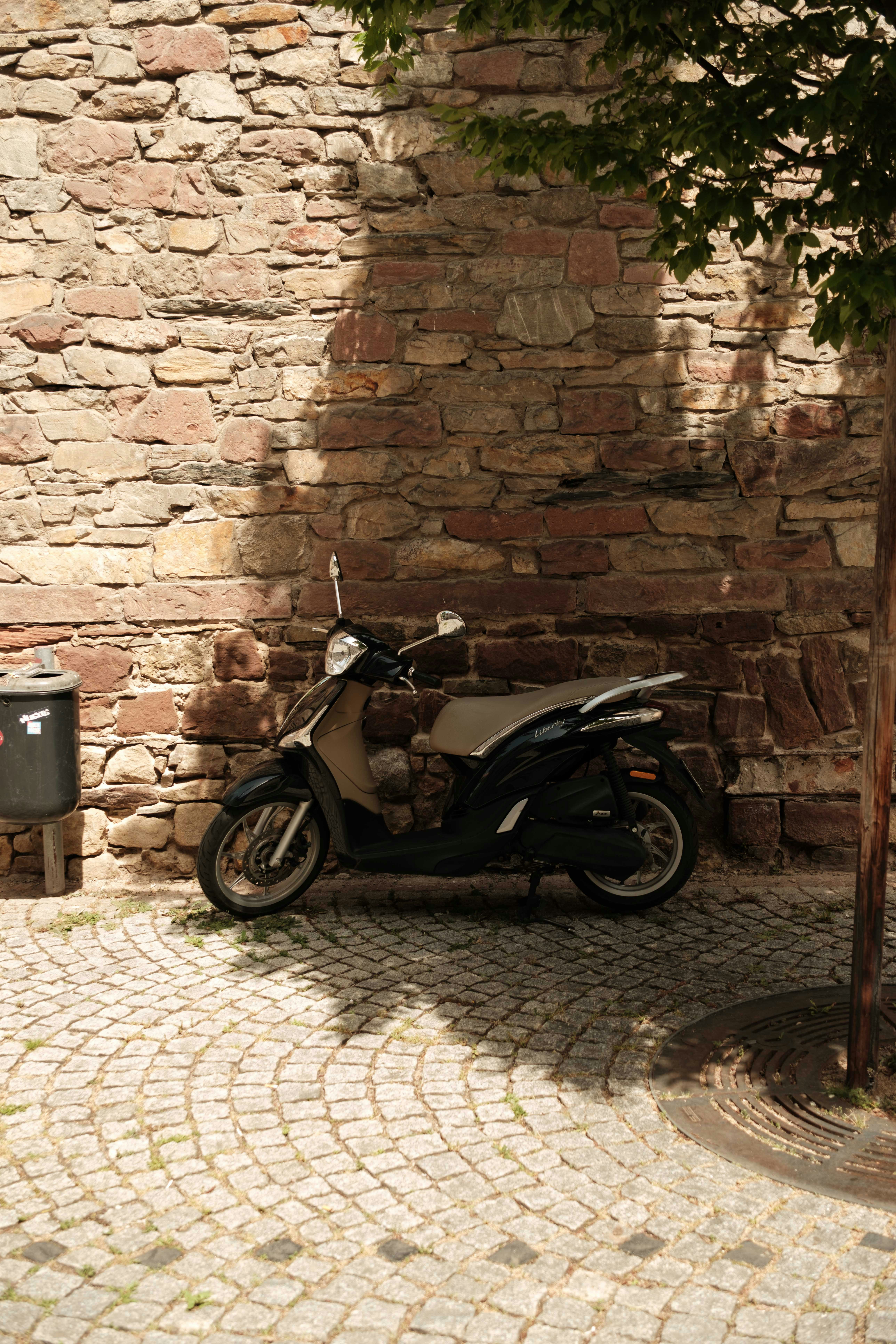 Sunlit Scooter Beside a Historic Wall