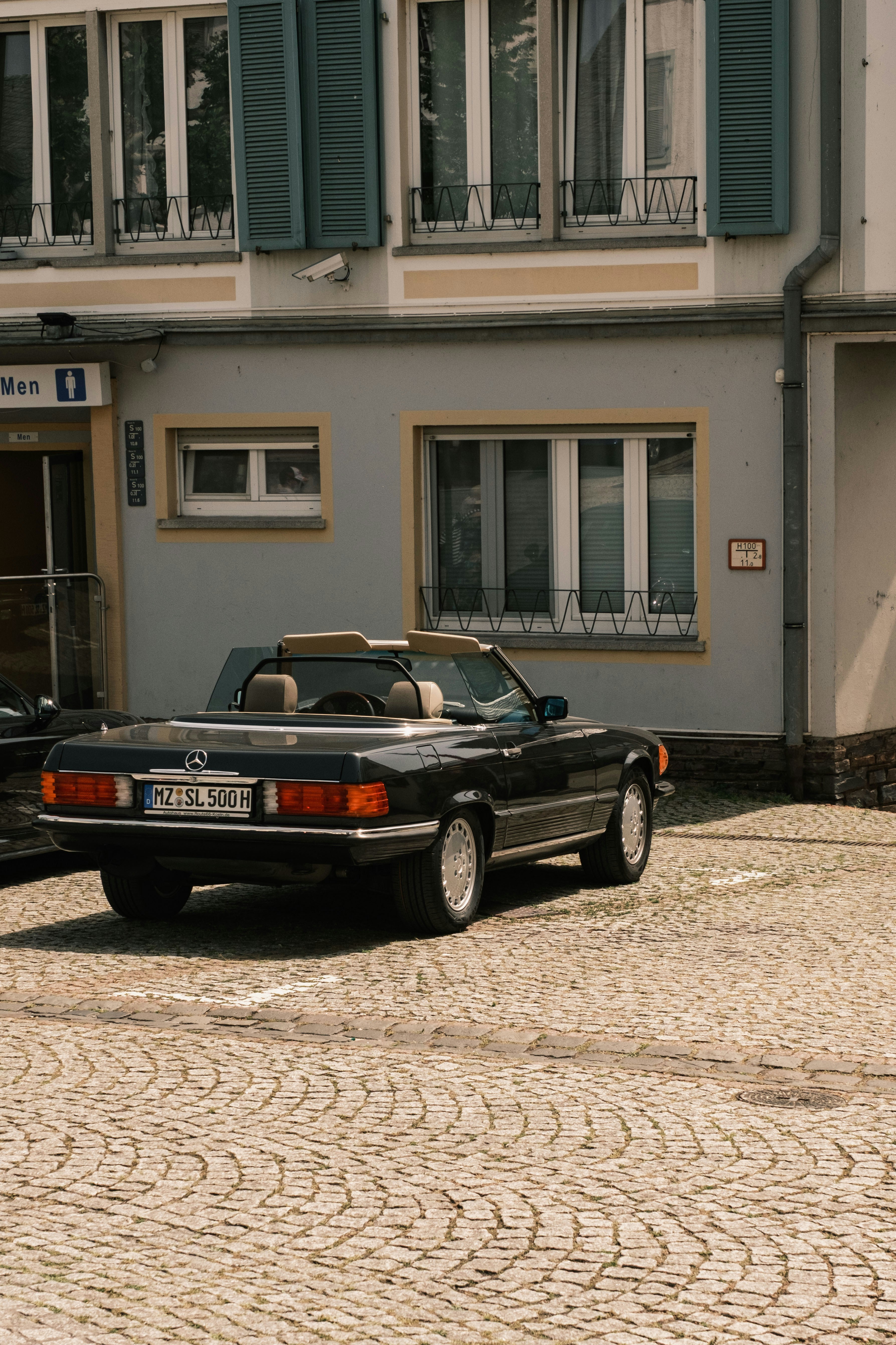 A black convertible car parked on a cobblestone street.