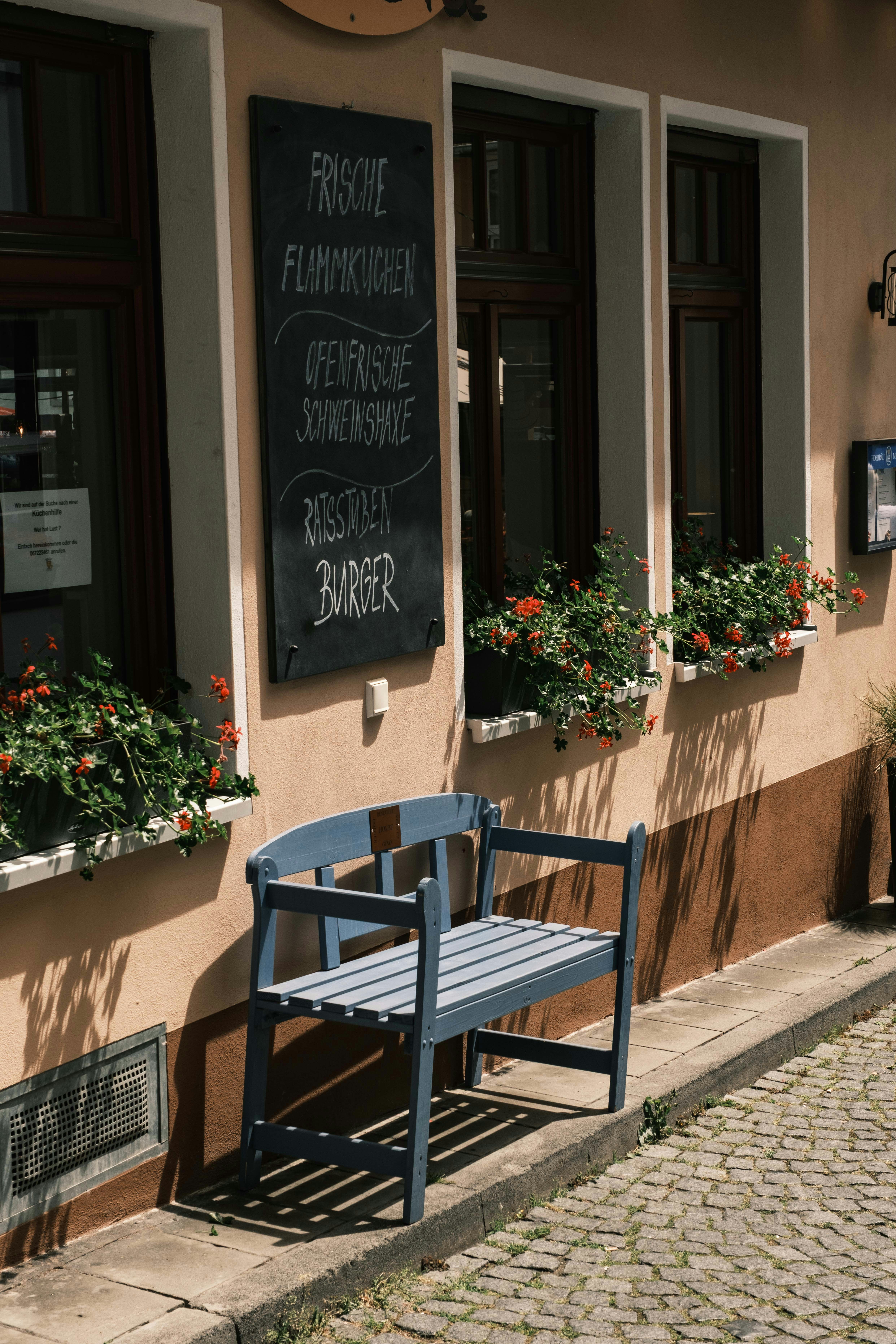 Blue bench beneath chalkboard menu in sunlit European street