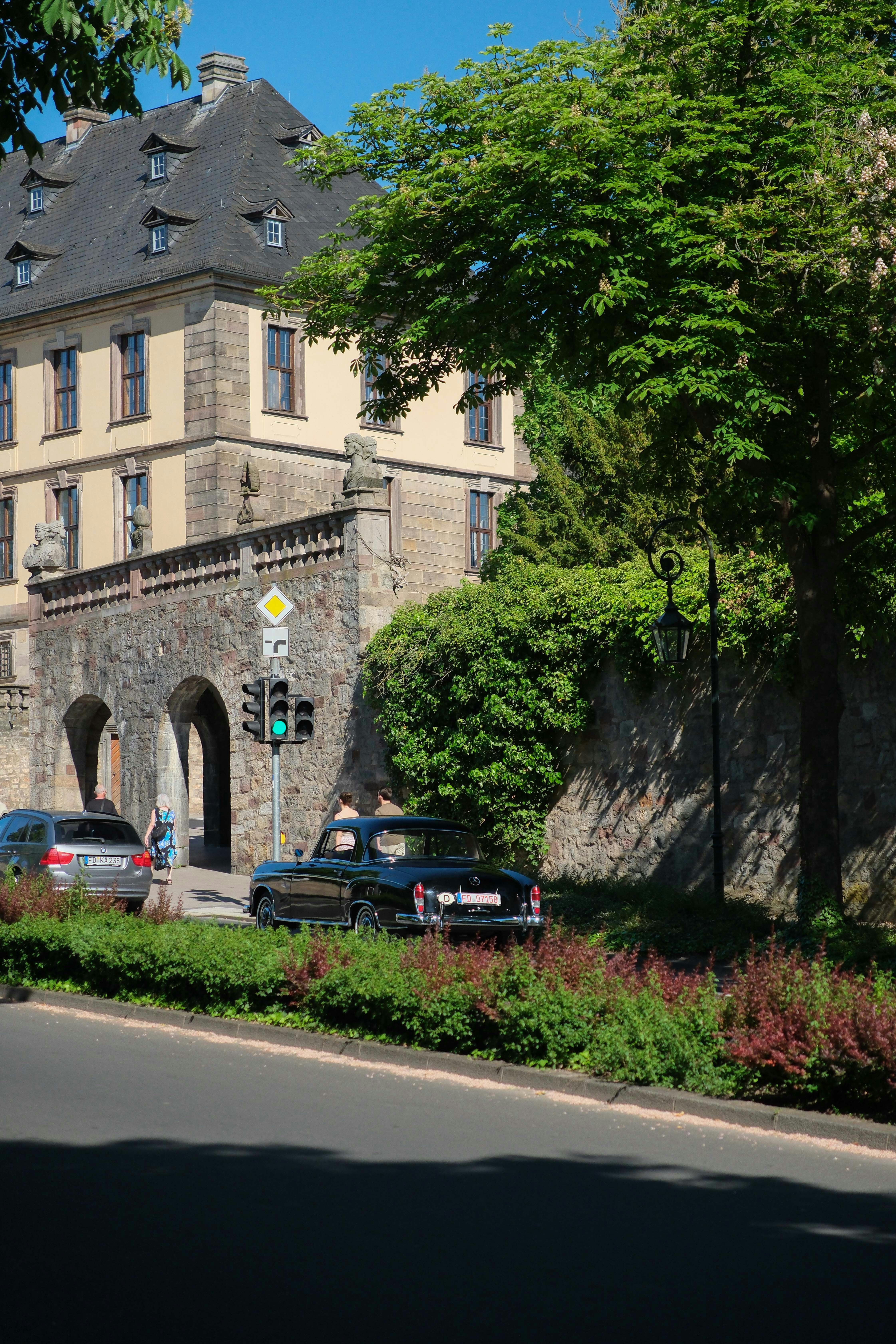 Historic Gatehouse and Classic Car on a Shaded City Lane
