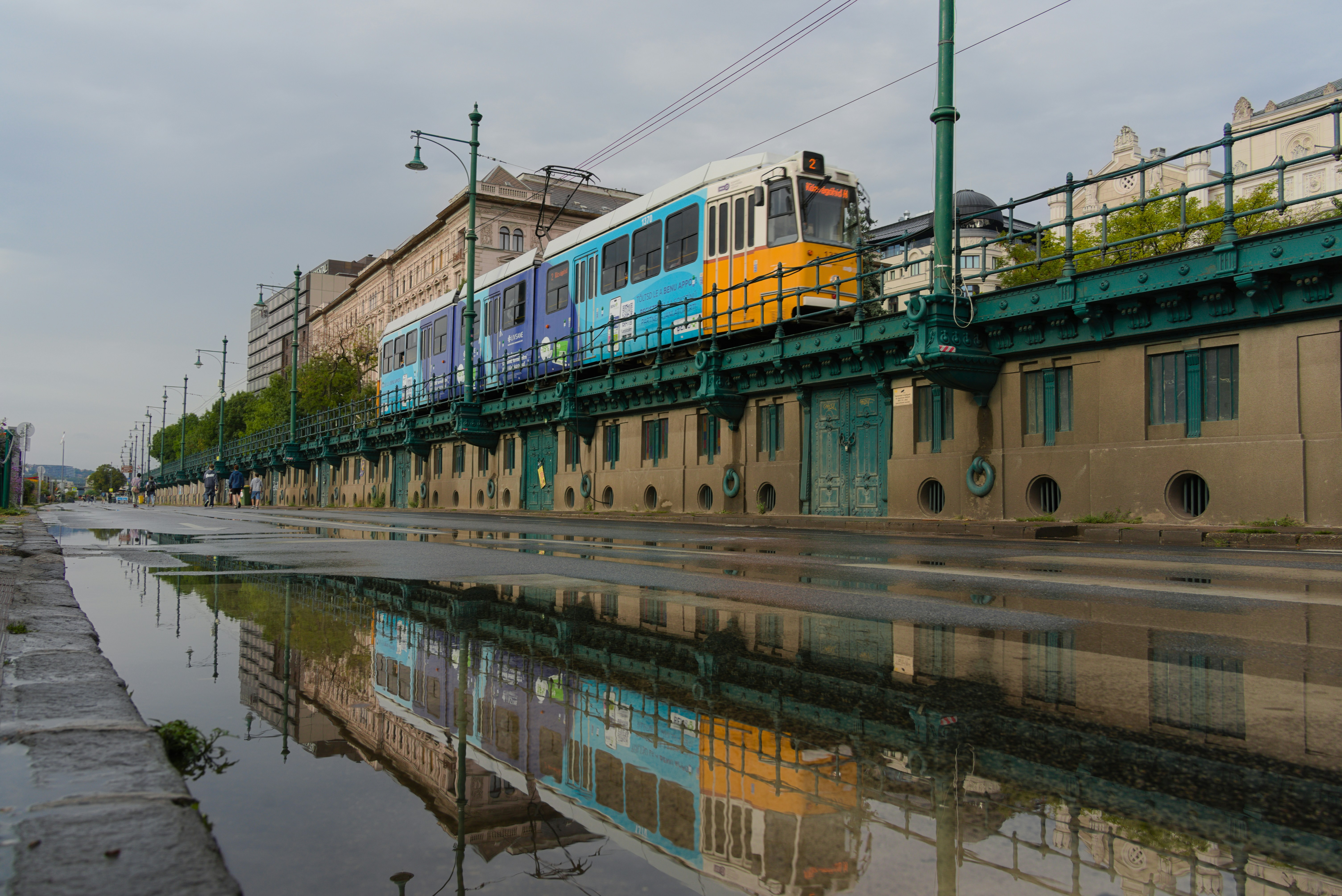 Colorful Tram Crossing Over a Reflective Riverbank