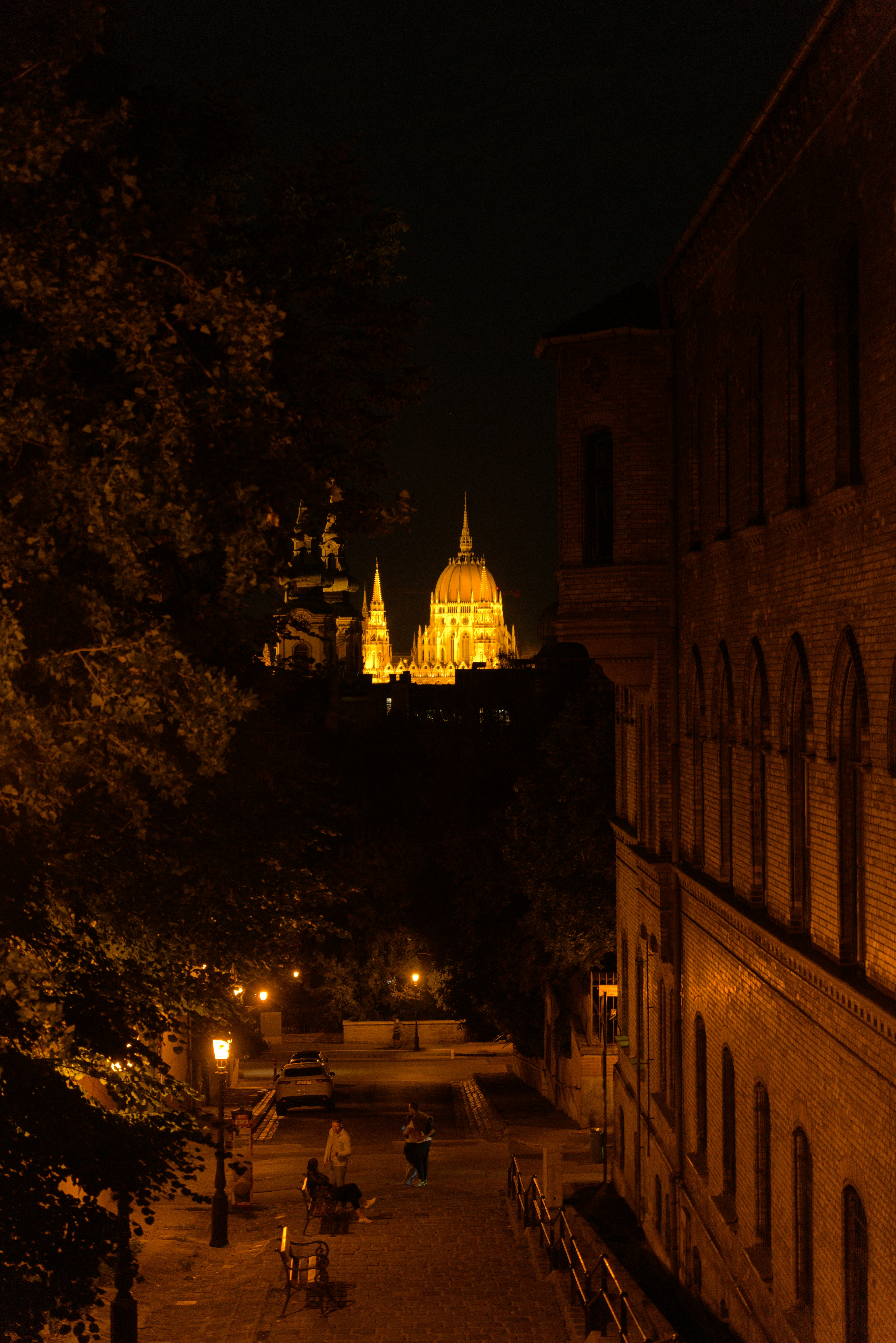  Lantern-lit Street Framing Budapest Greens: Nighttime Arc to the Parliament Dome