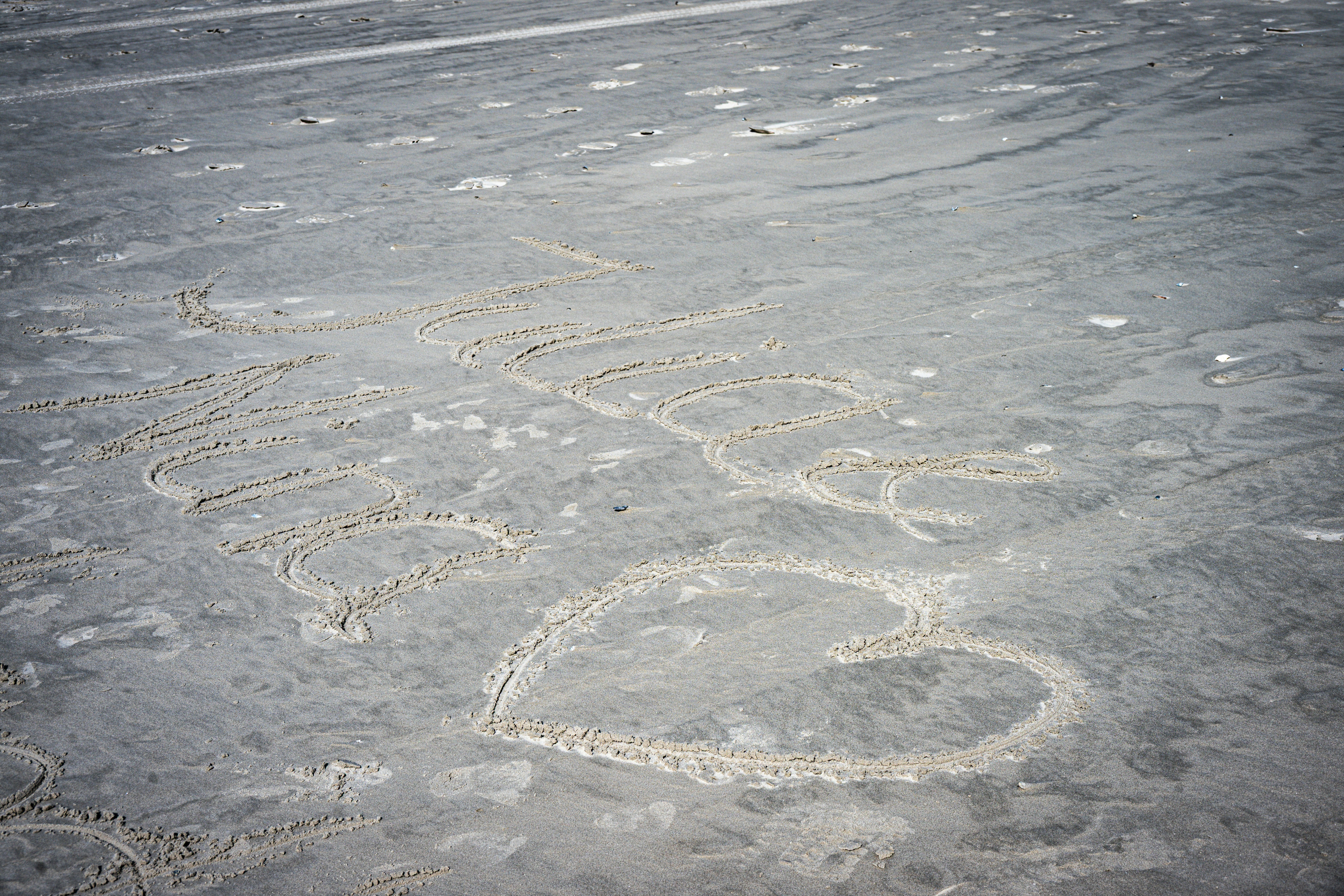 Heart and 'love' drawn in dry, sandy ground.