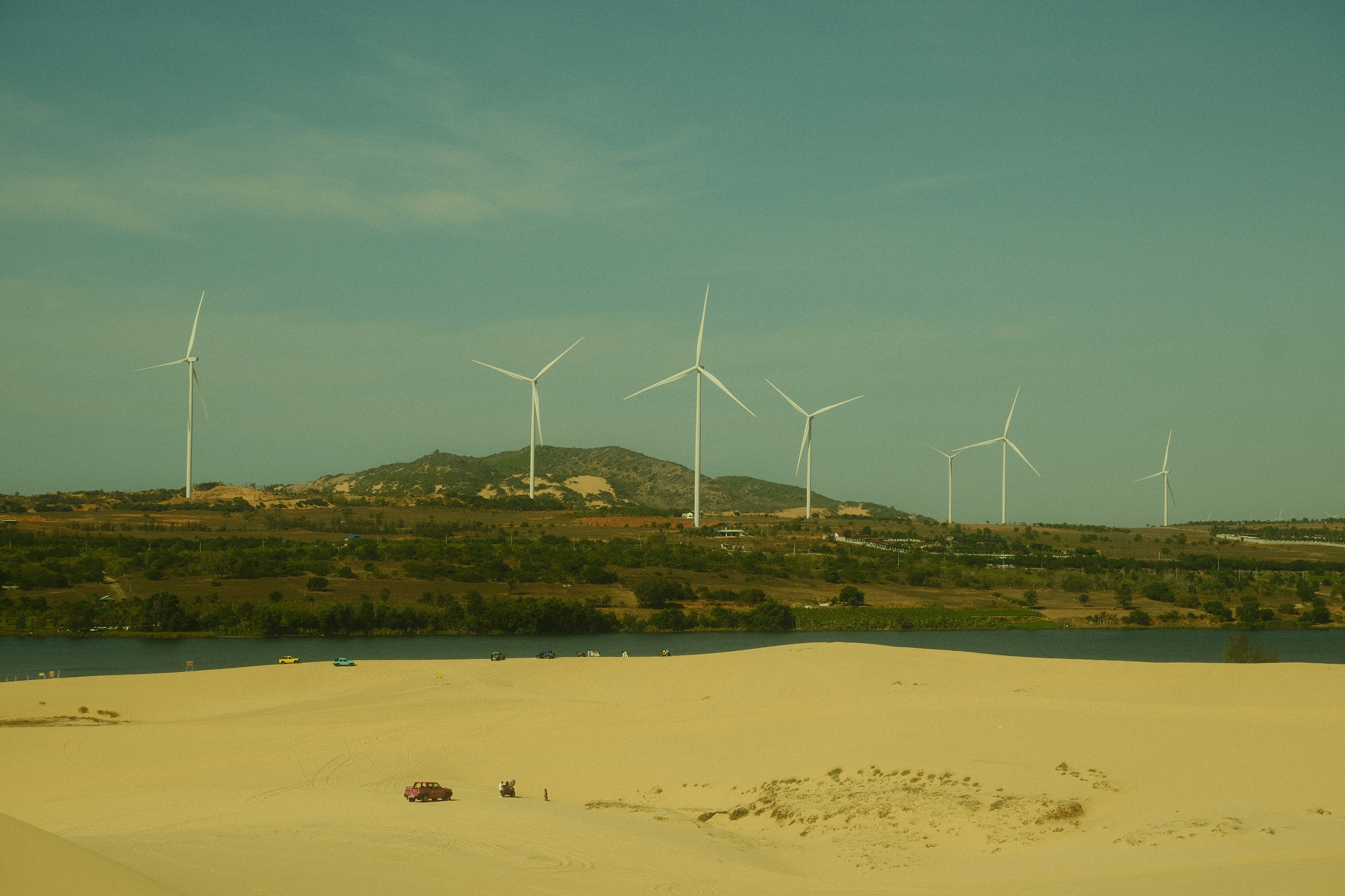 Breeze Over the Dunes: A Row of Wind Turbines Silhouetted Against a Golden Landscape
