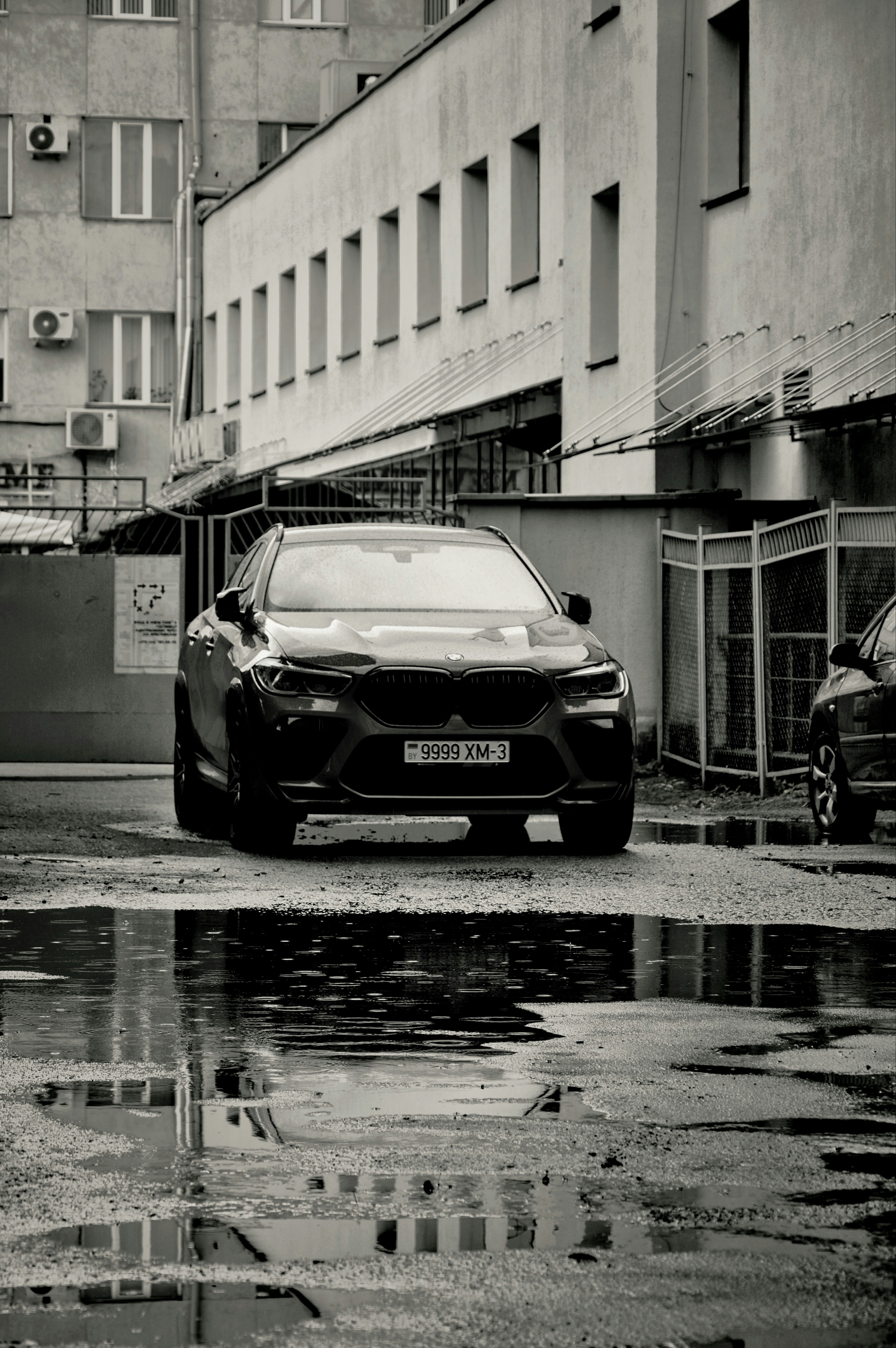 Midtown Stare: A Bold Car Mirror in a Wet Concrete Yard