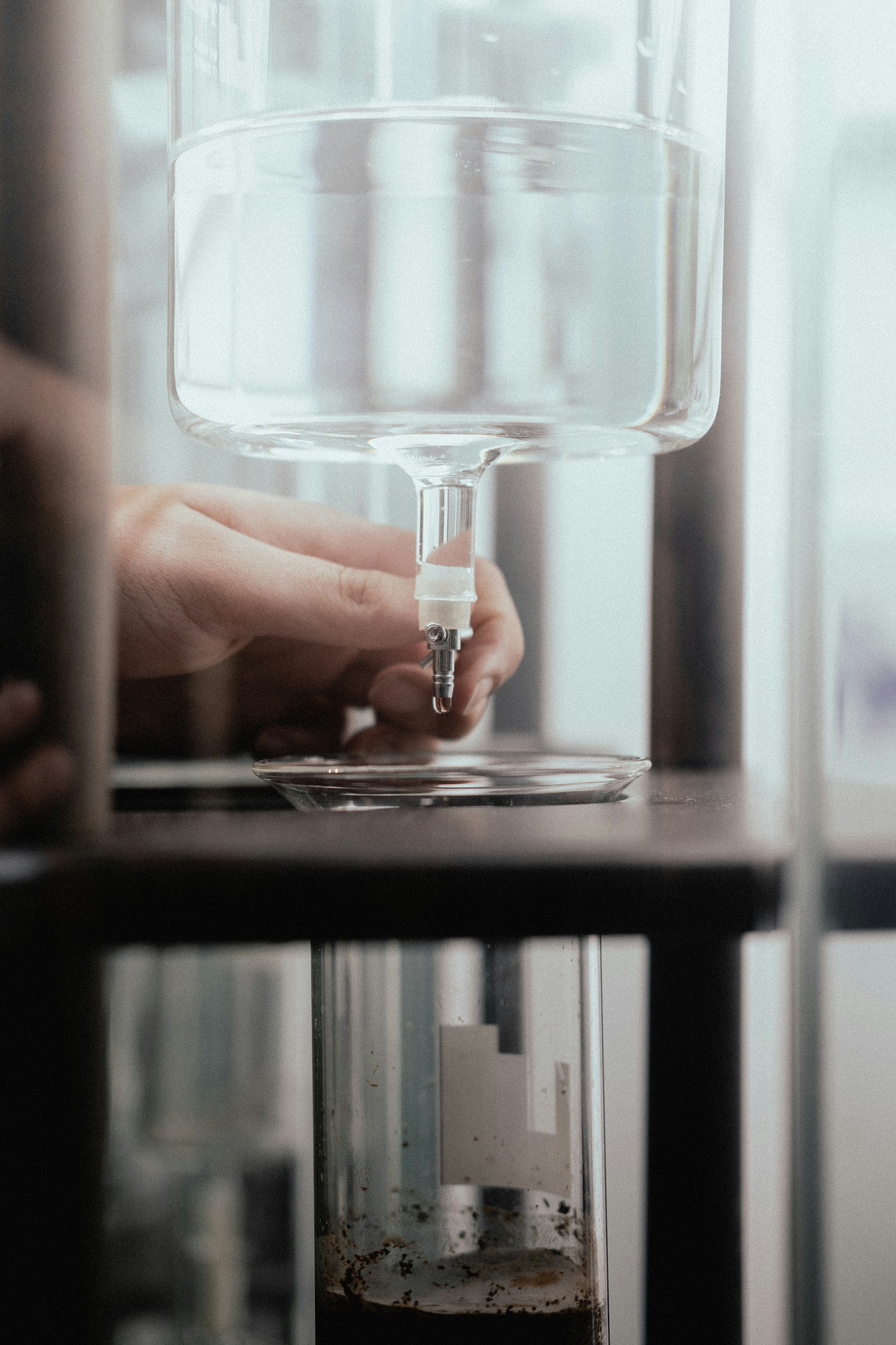 A hand adjusts a cold brew coffee maker.