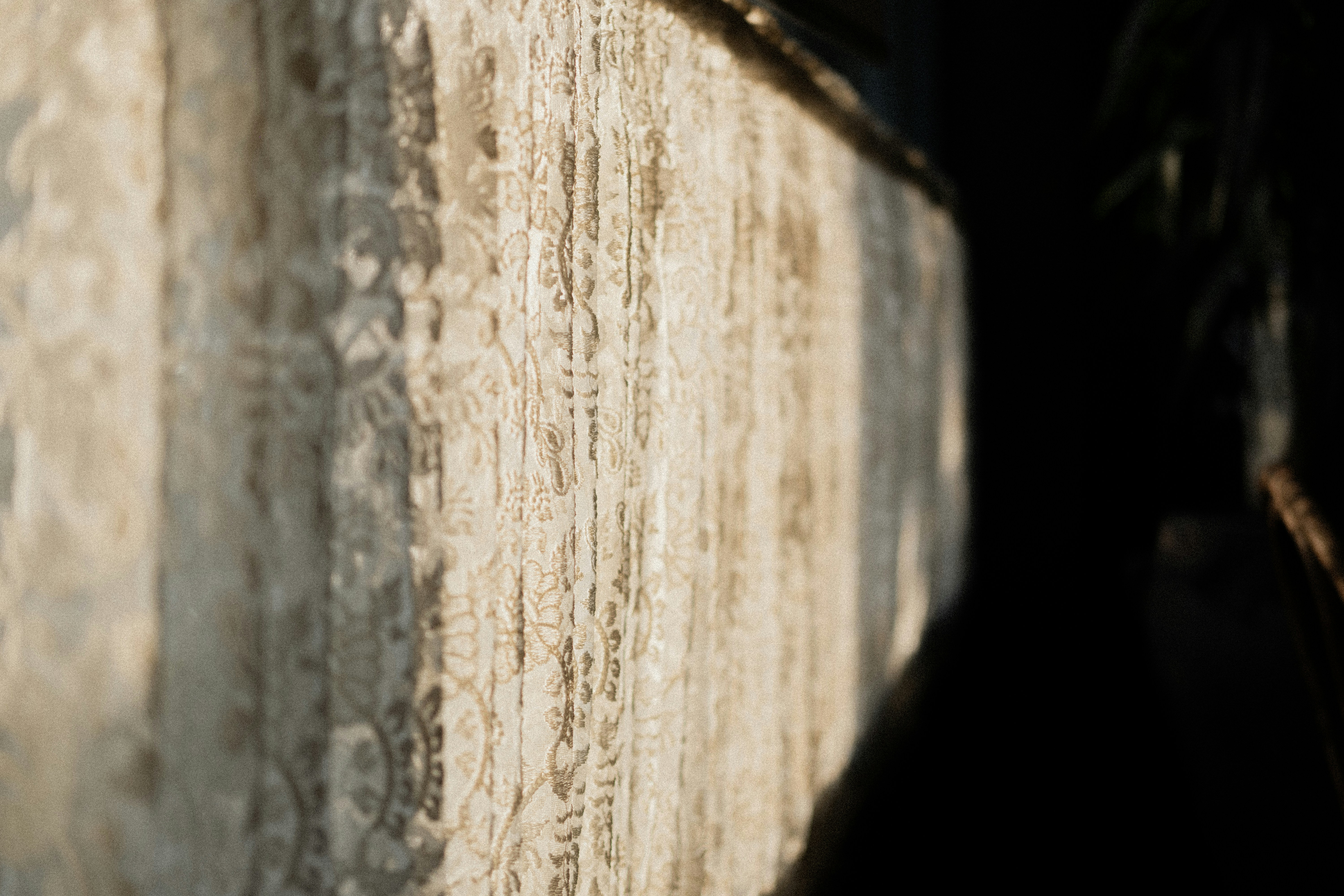 Sunlight illuminates ancient stone carvings on a textured wall.