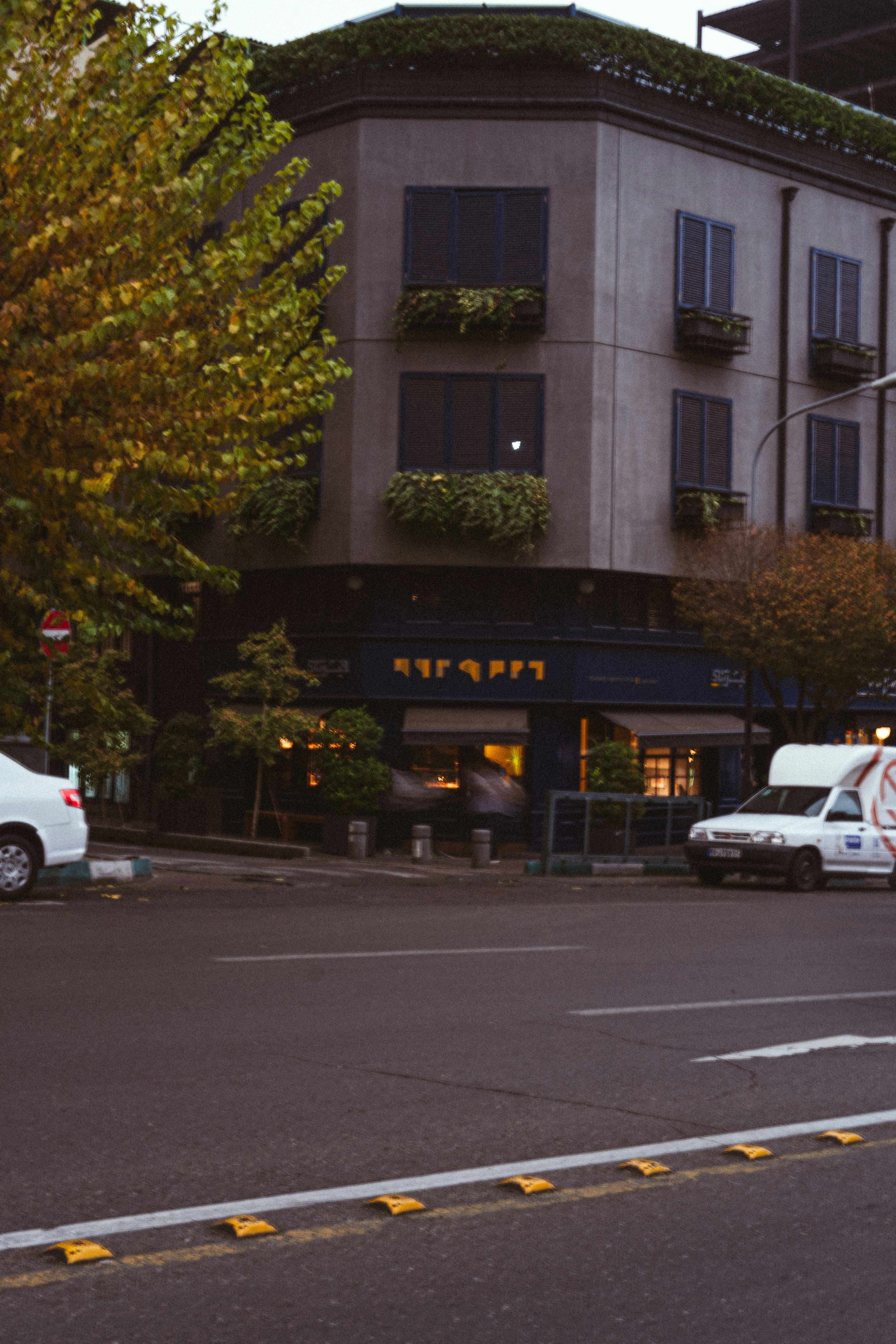 City street scene with a dark building and autumn trees.