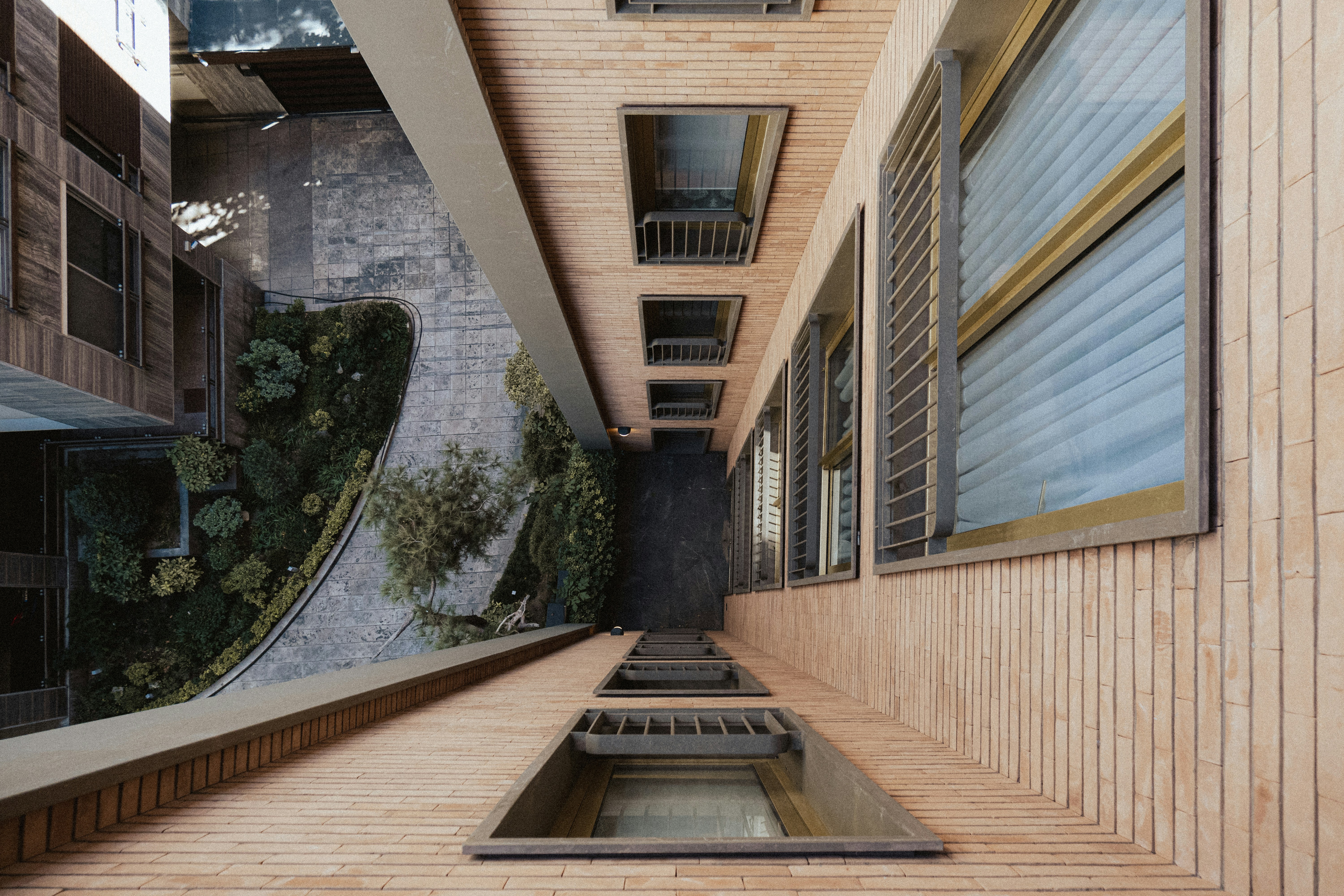 Looking down a tall building with windows and a courtyard.