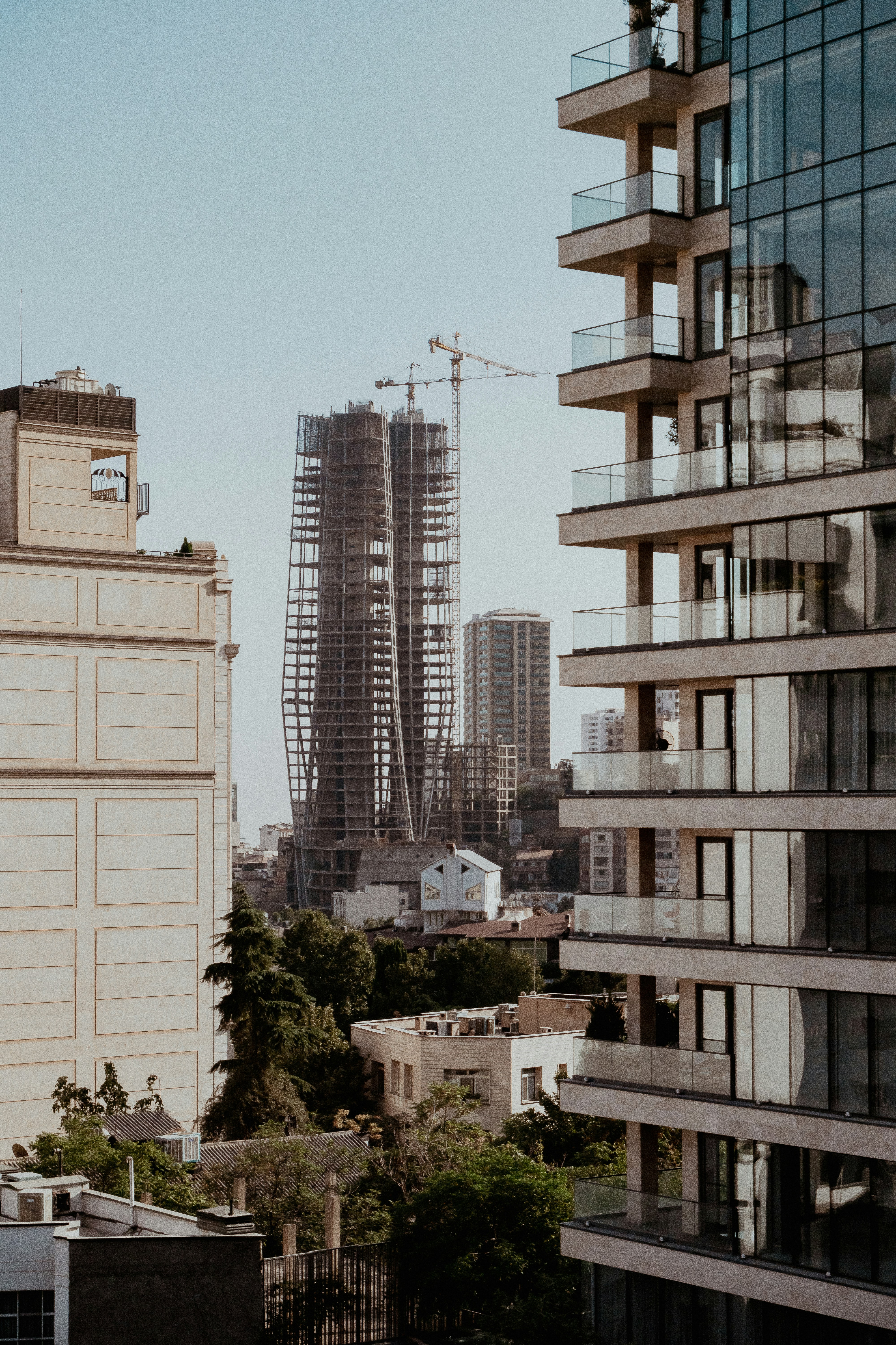 Urban skeleton rising: a crane-laced skyline between glass and concrete