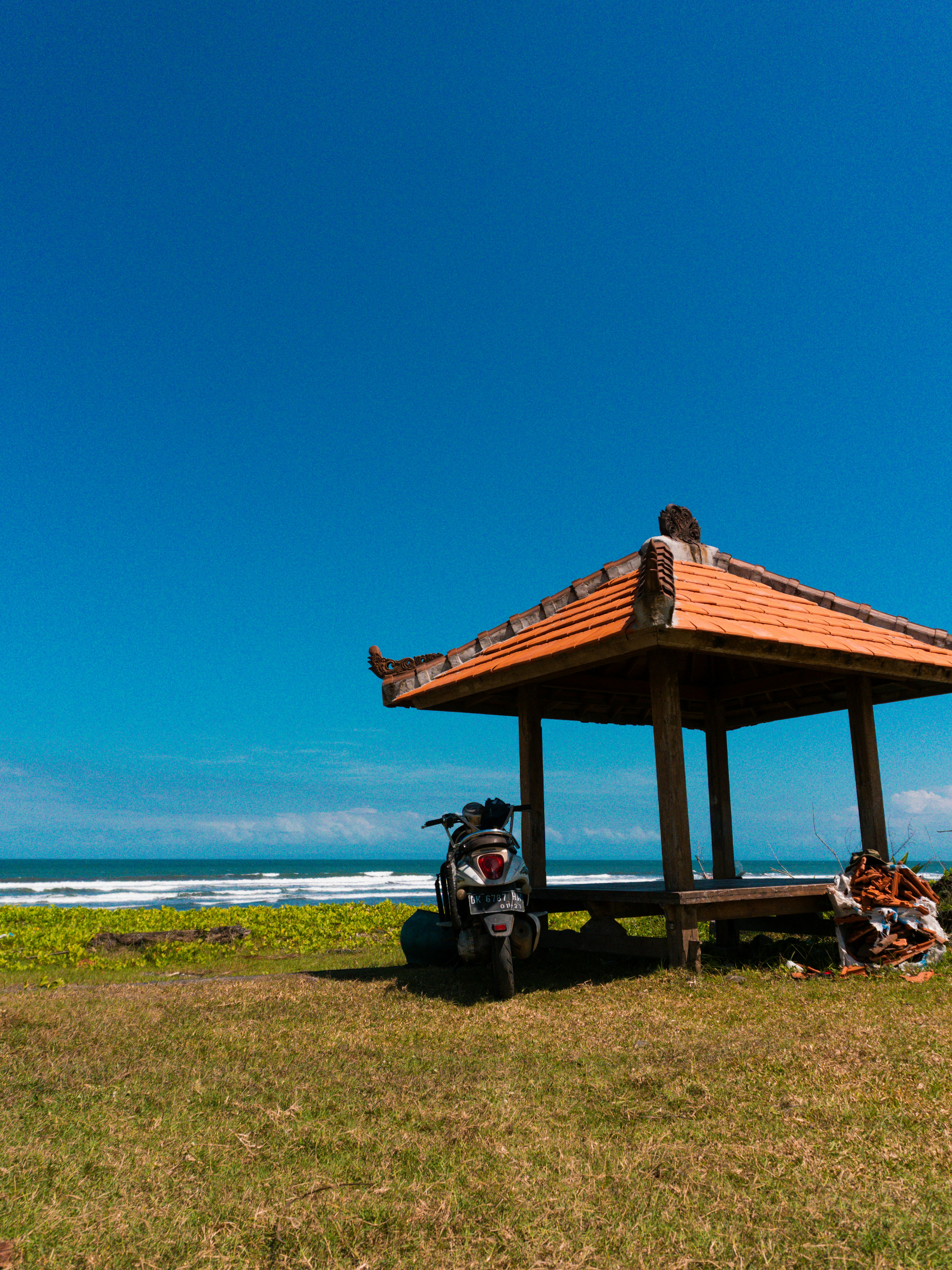 Coastal Shelter: A Scooter Resting by the Pavilion