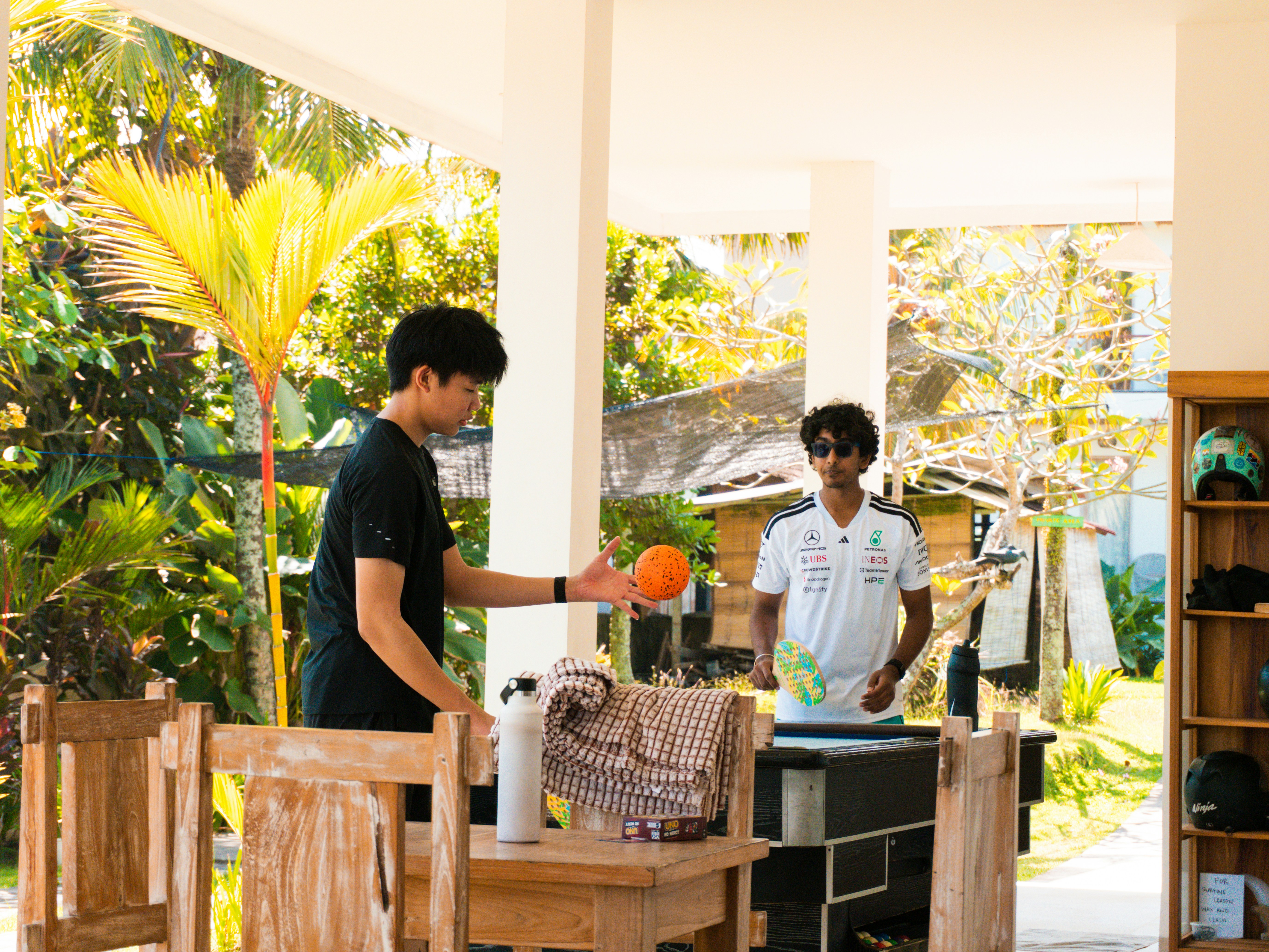Two men conversing in an outdoor tropical kitchen.