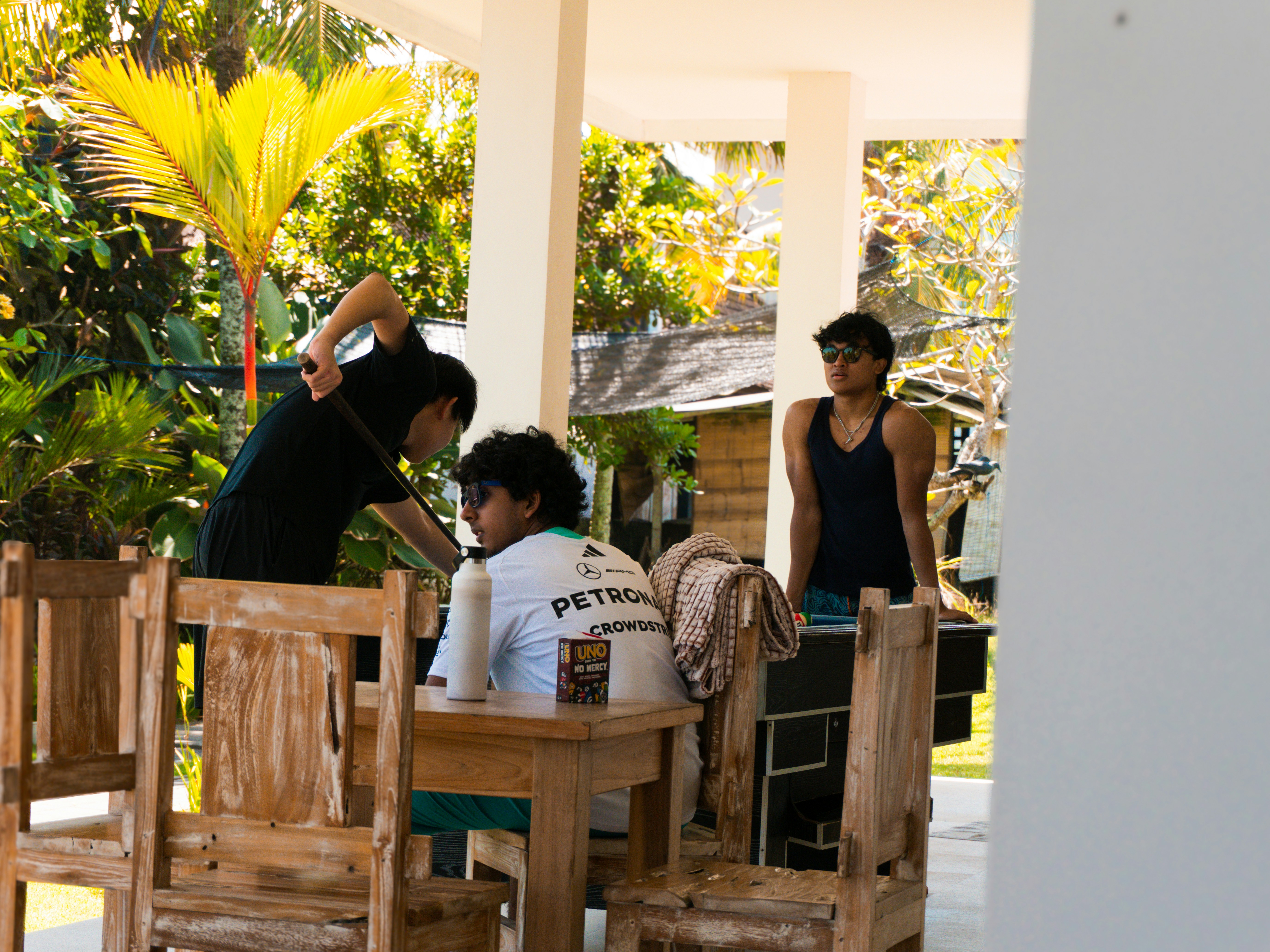 Group of friends at a sunlit outdoor cafe in a tropical setting