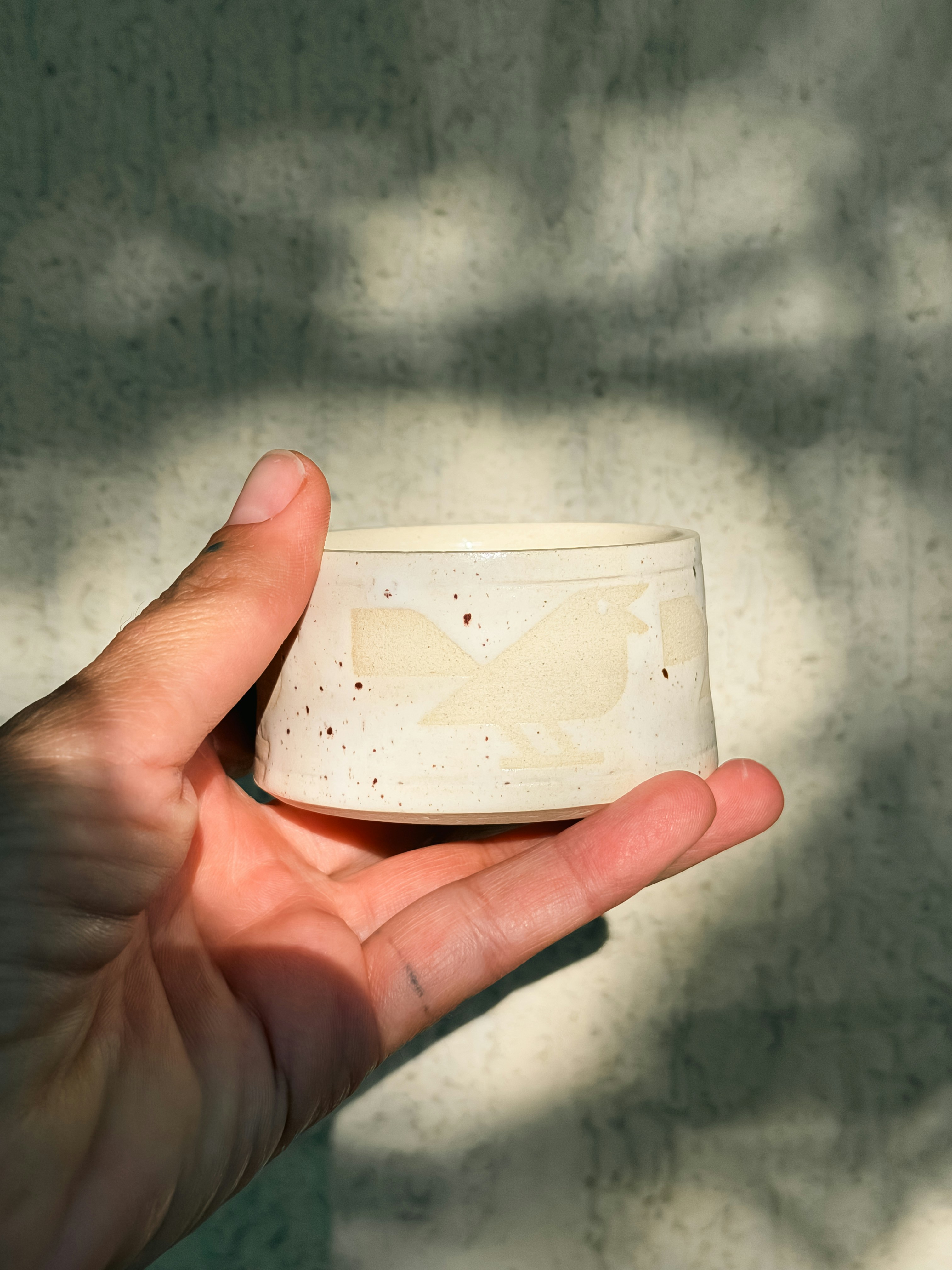 Holding a Minimalist Ceramic Cup Against a Shadowed Wall