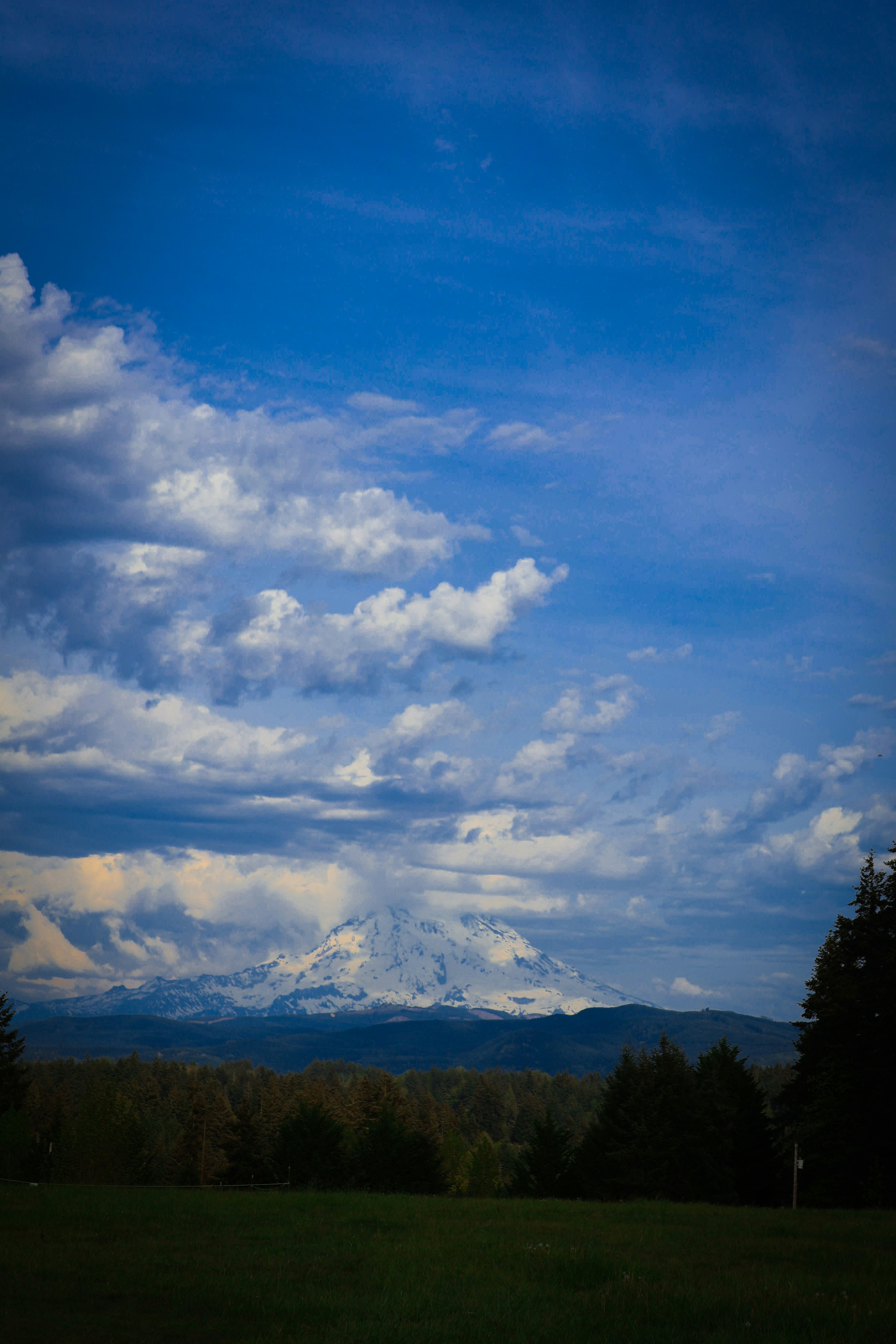 A majestic snow-capped mountain under a dramatic cloudy blue sky.